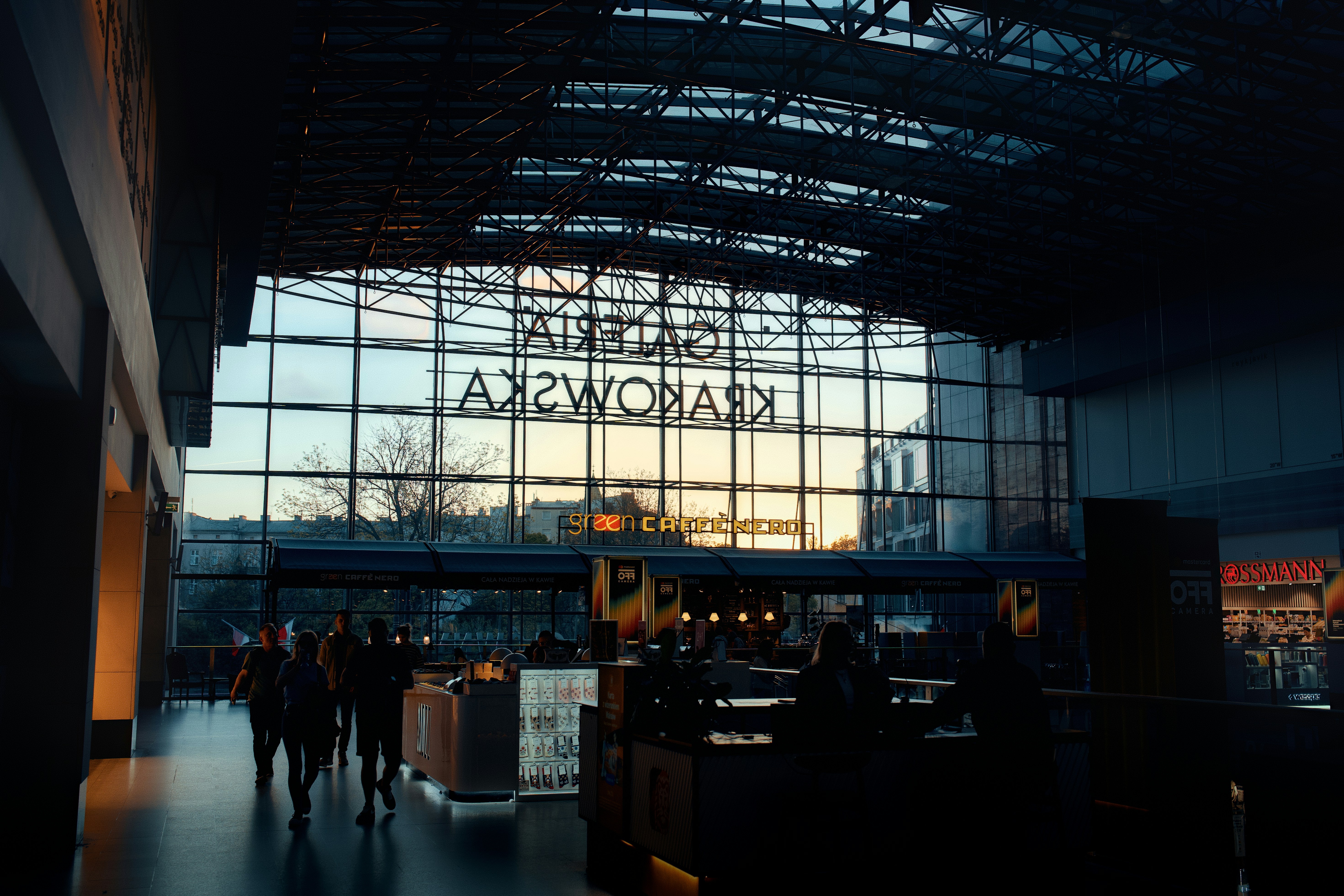 Glass-Cweled Atrium at Dusk: People Flow Beneath the Sky-Frame
