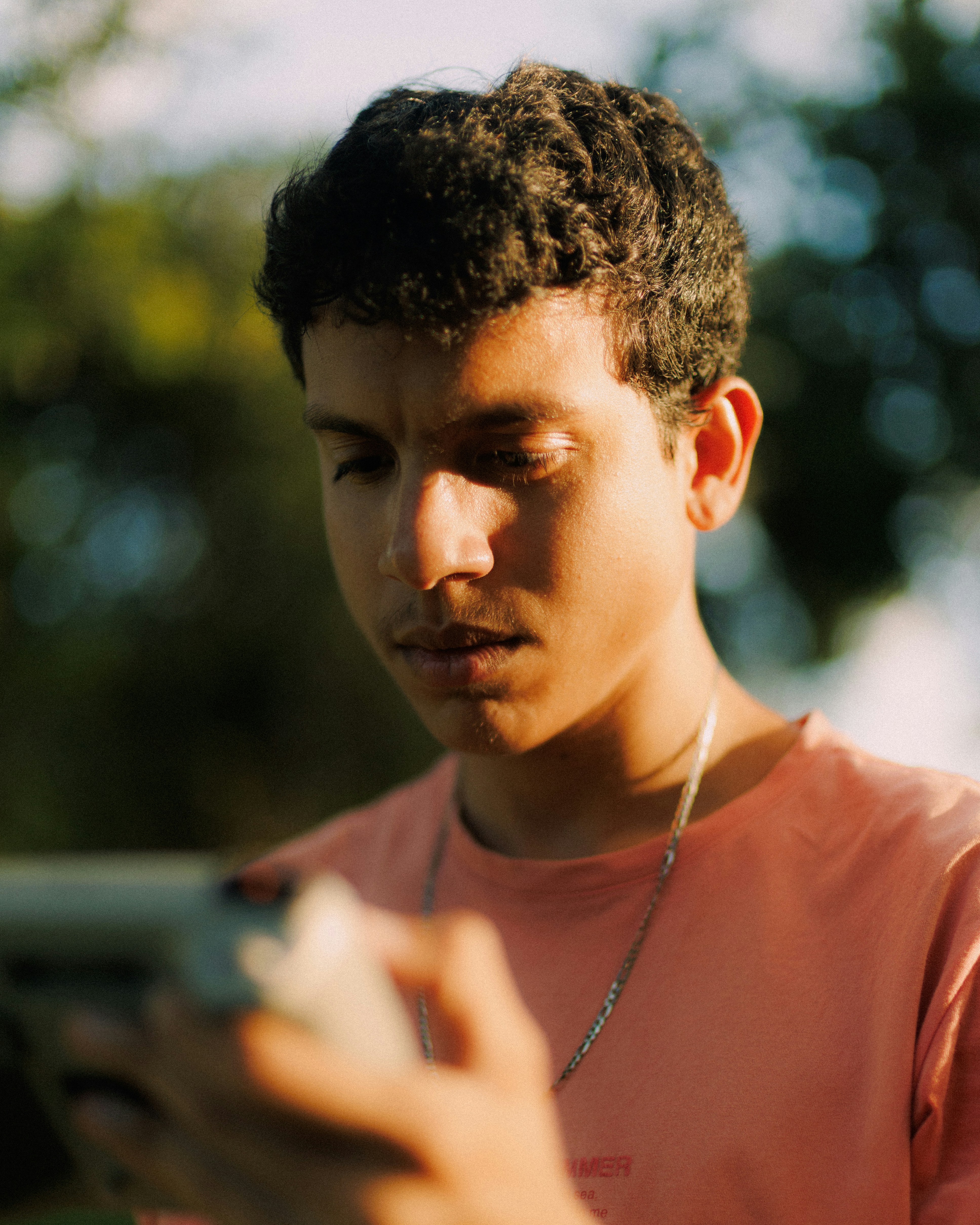 Young man looking at his phone outdoors in sunlight.
