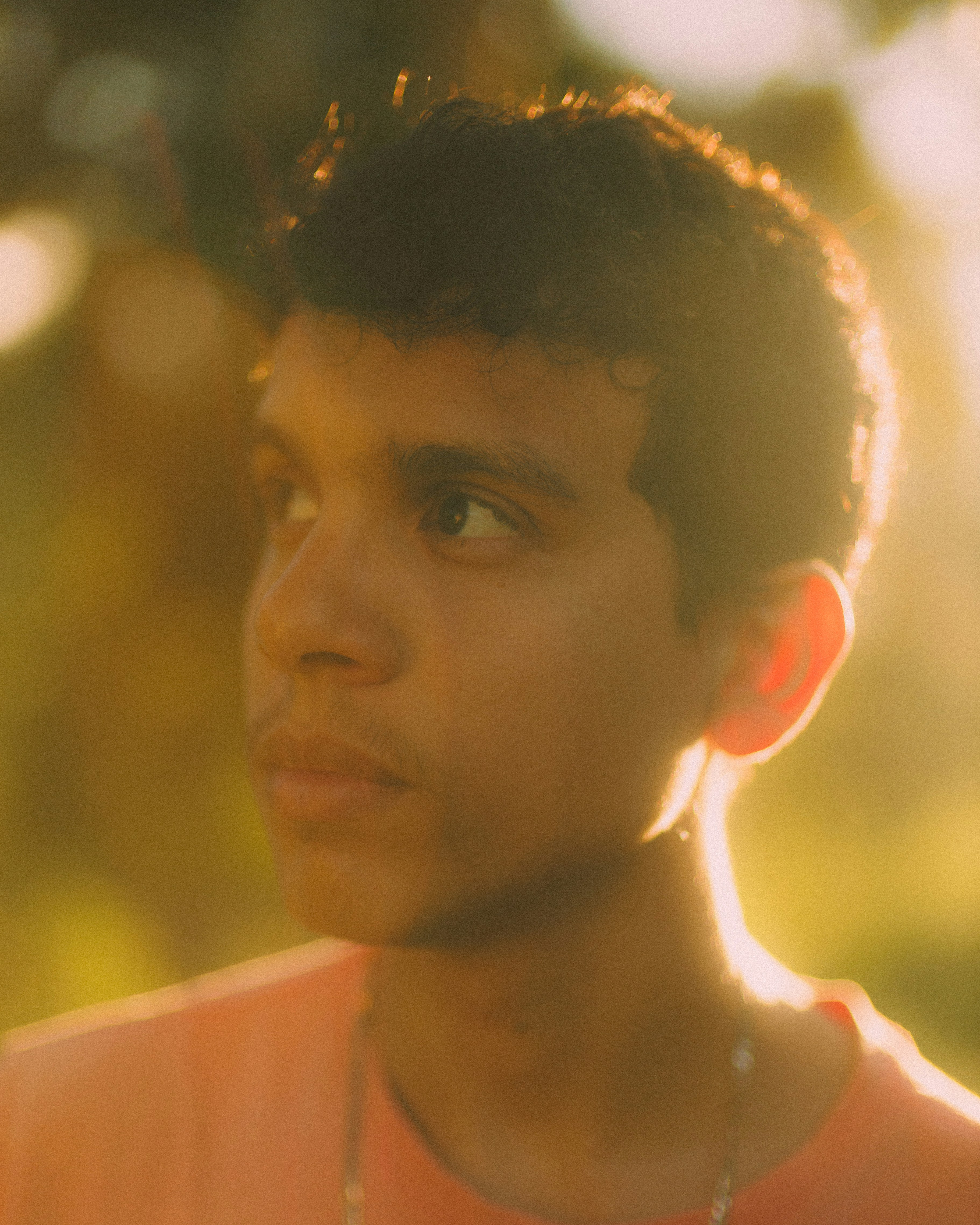 A young man looking sideways with golden hour sunlight.