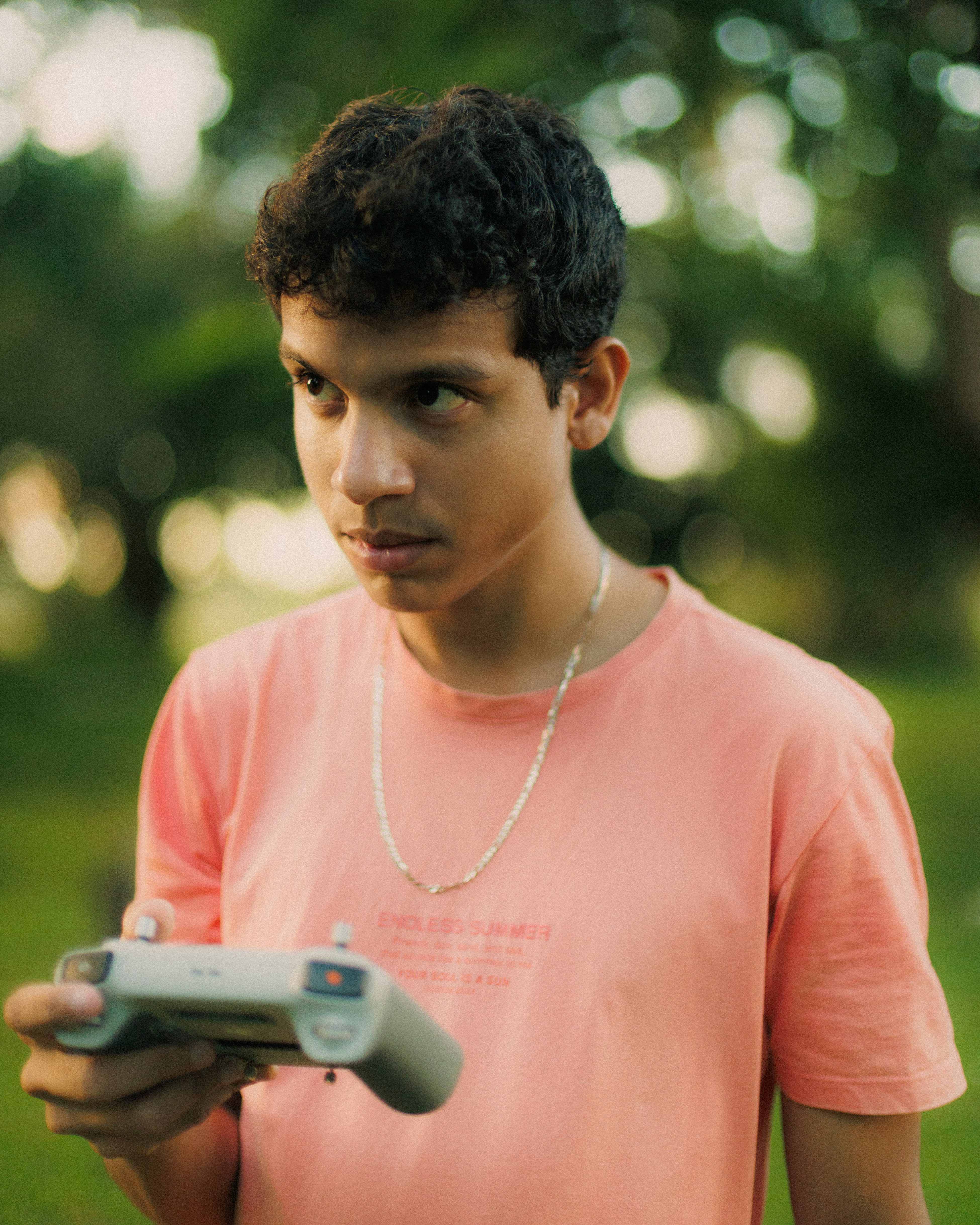 Young man intently holding a remote controller outdoors.
