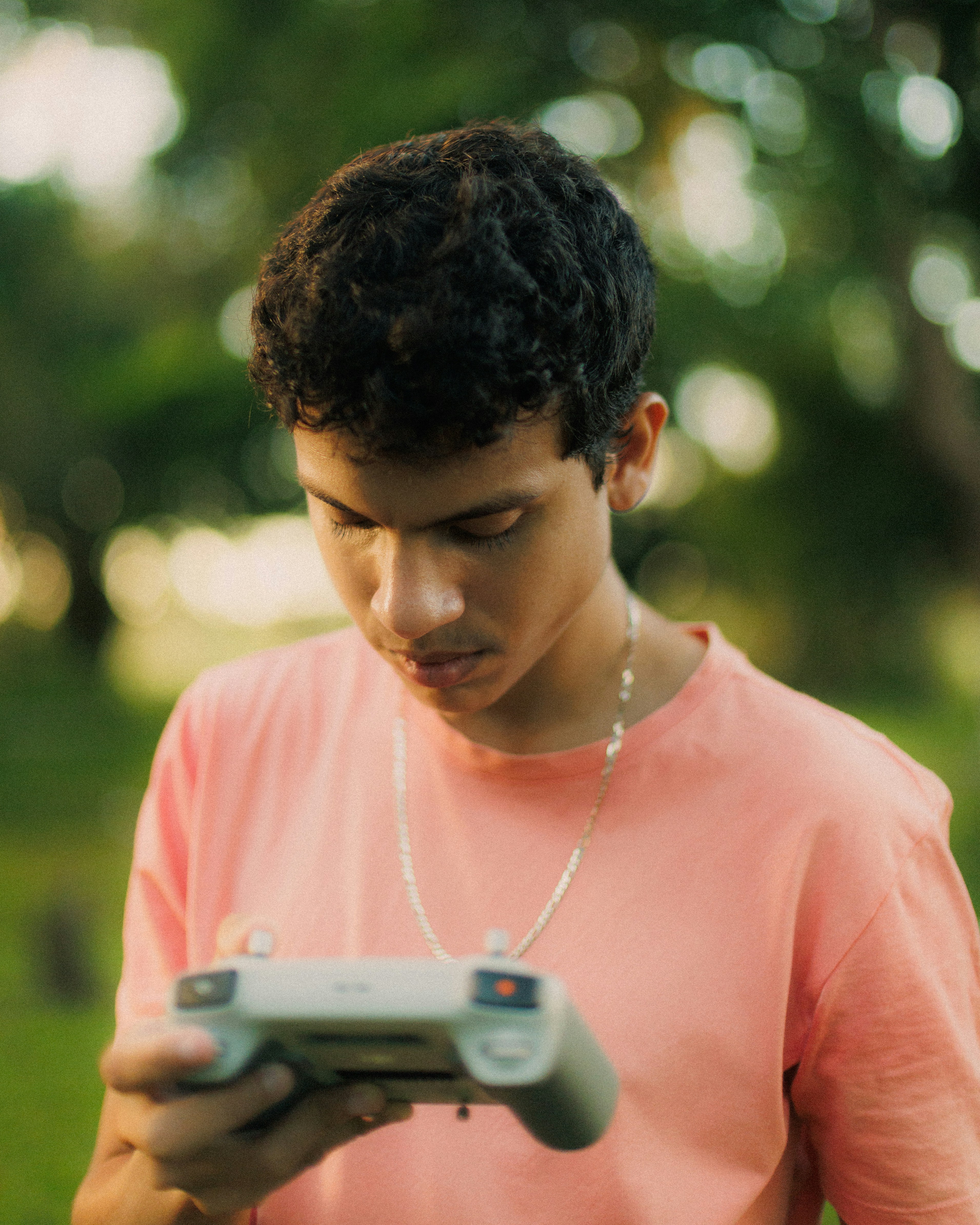 Soft Focus Moment: A Teenager Concentrates on a Retro Console in a Sunlit Park