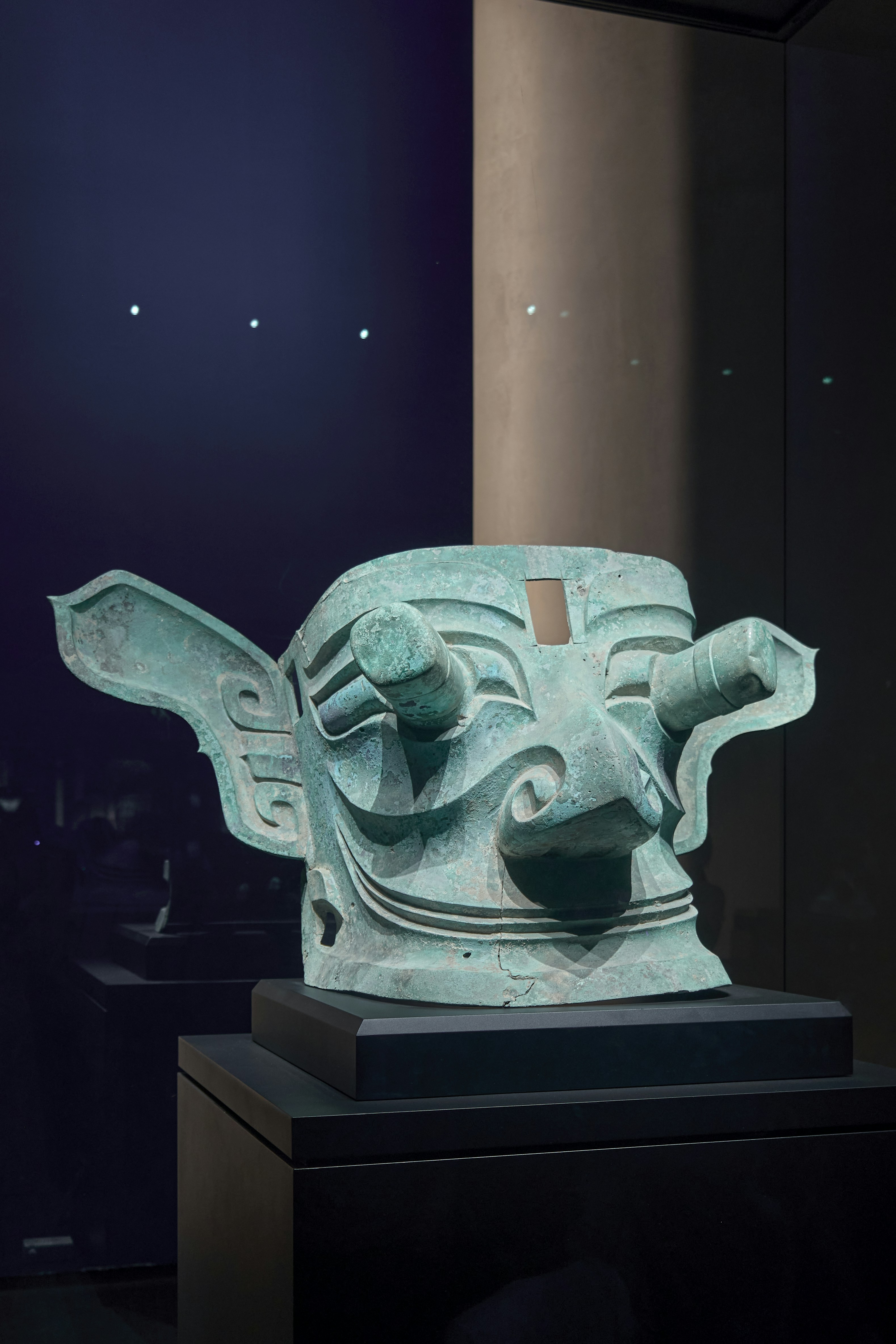 Bronze Guardian: Ancient Mask Emerges from Velvet Darkness