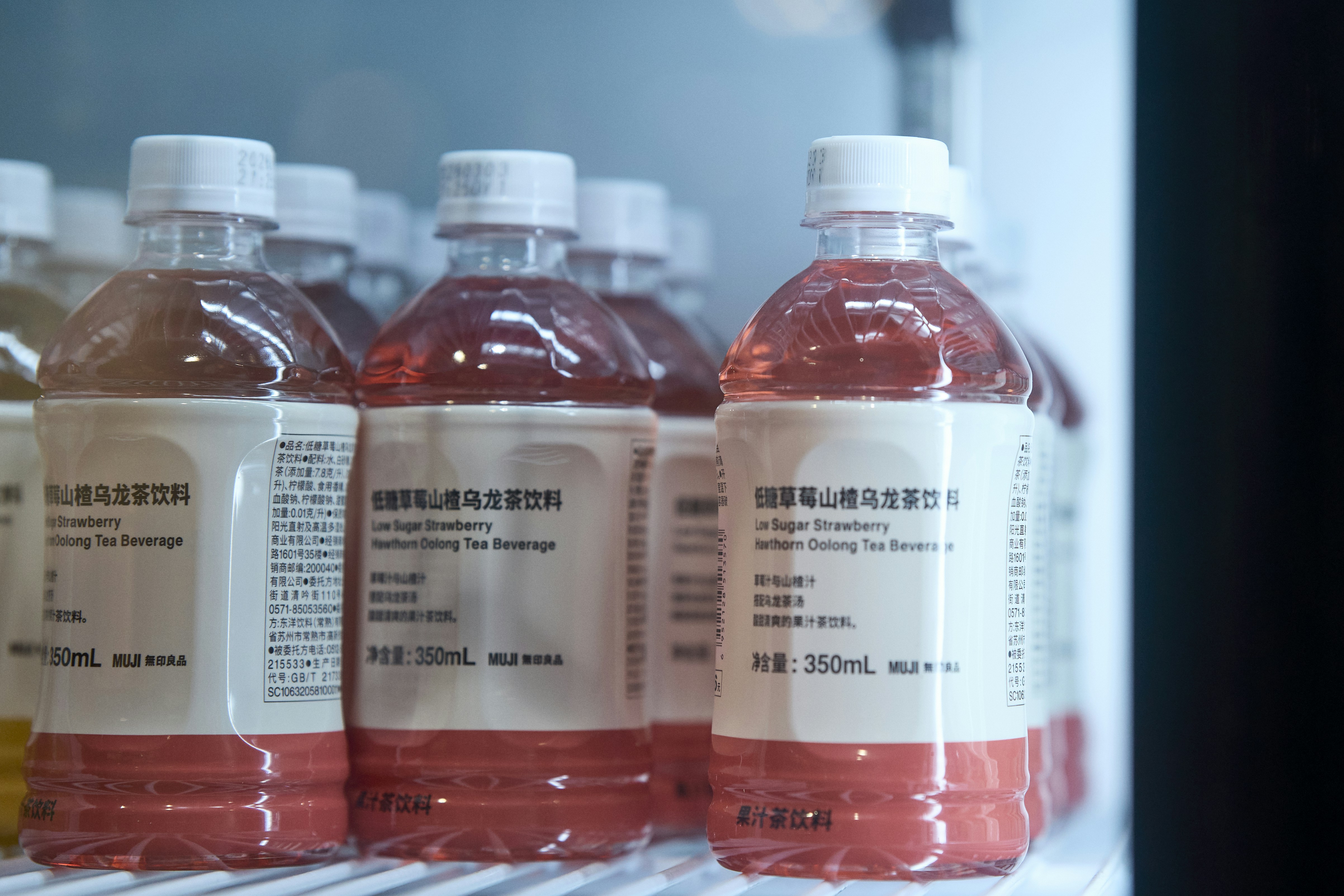 Rows of red liquid bottles on a store shelf.