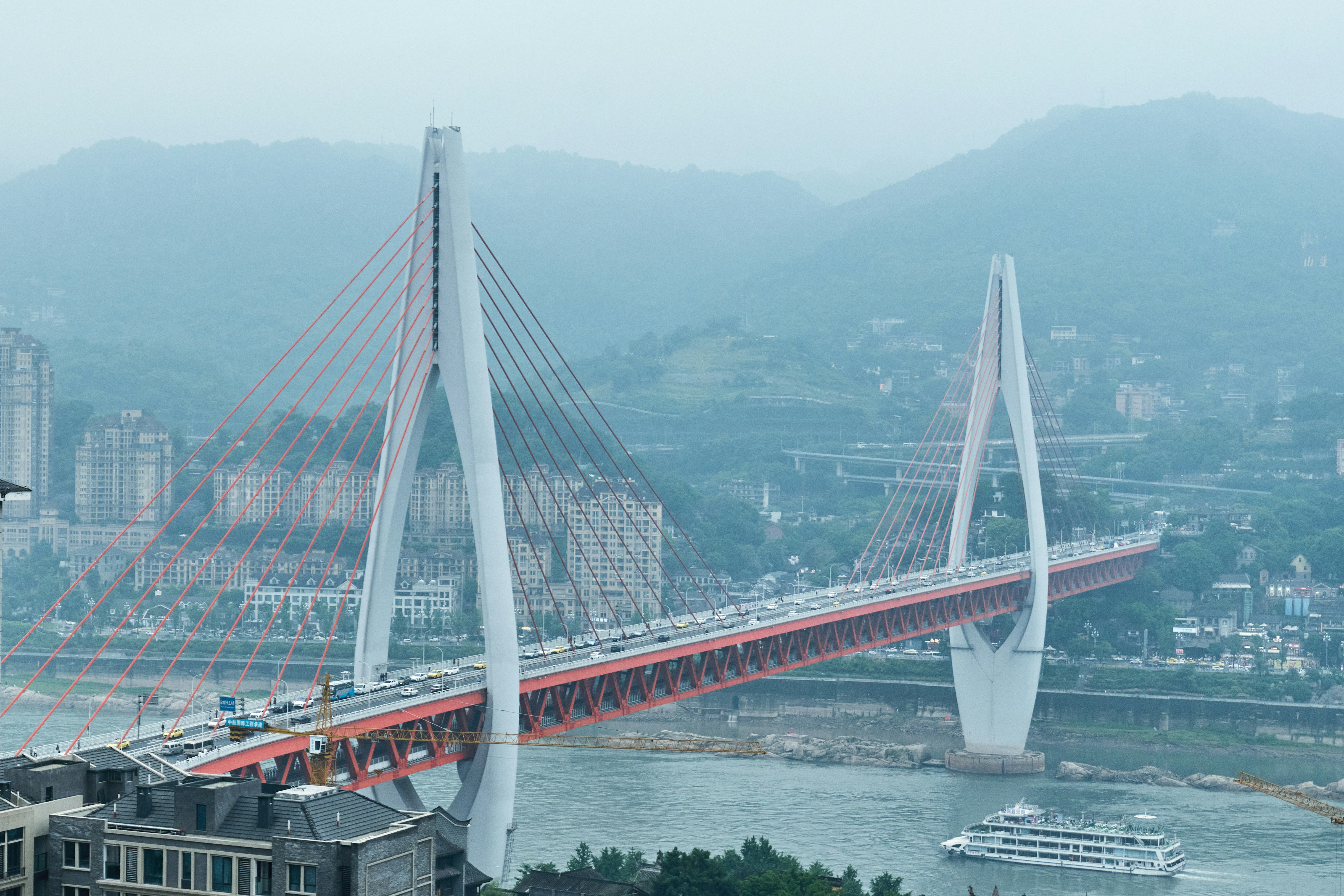 Red Cable-Decked Arc: A Modern Bridge Framing a Riverine City