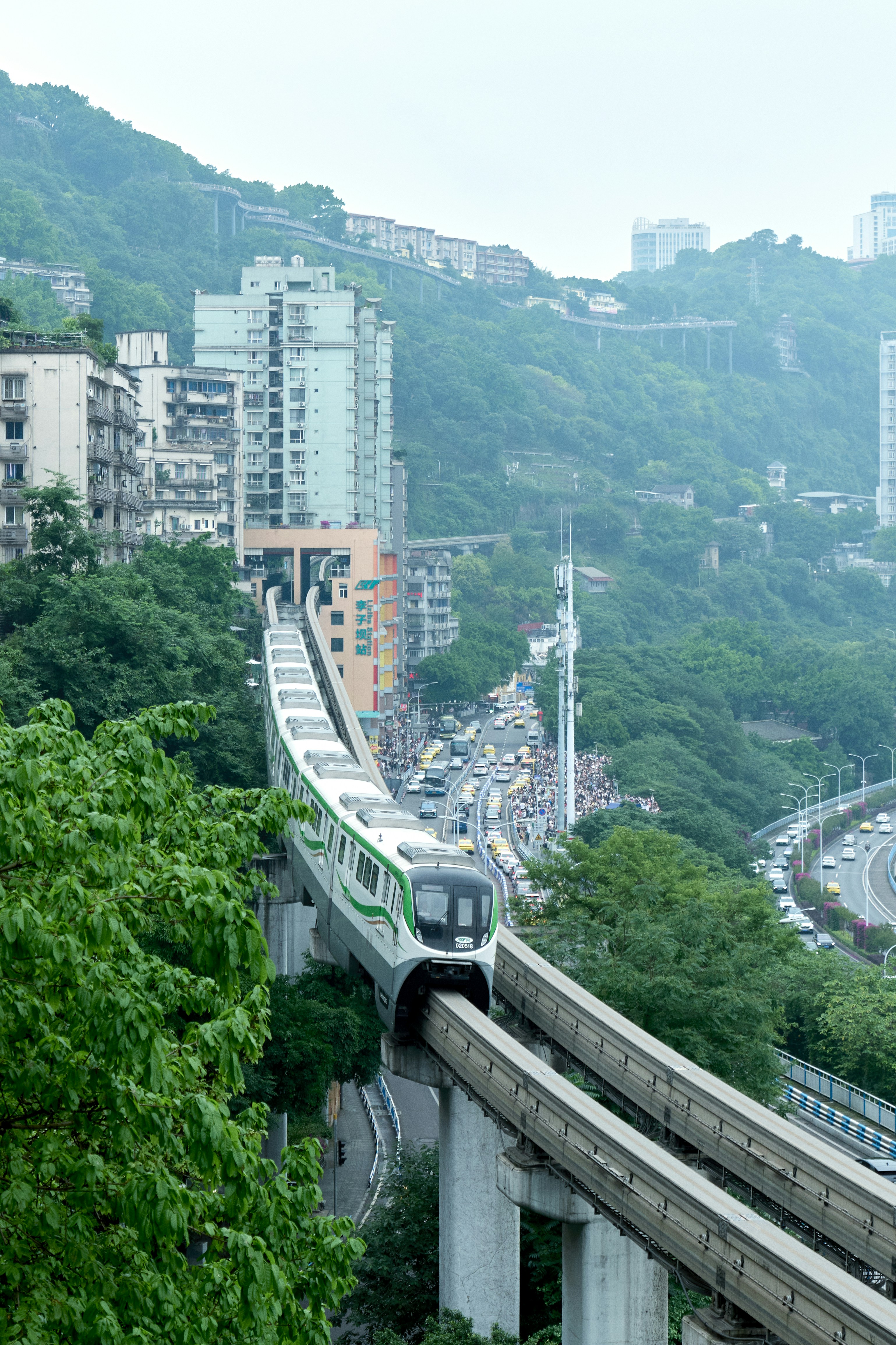 A monorail train travels through a hilly city landscape.