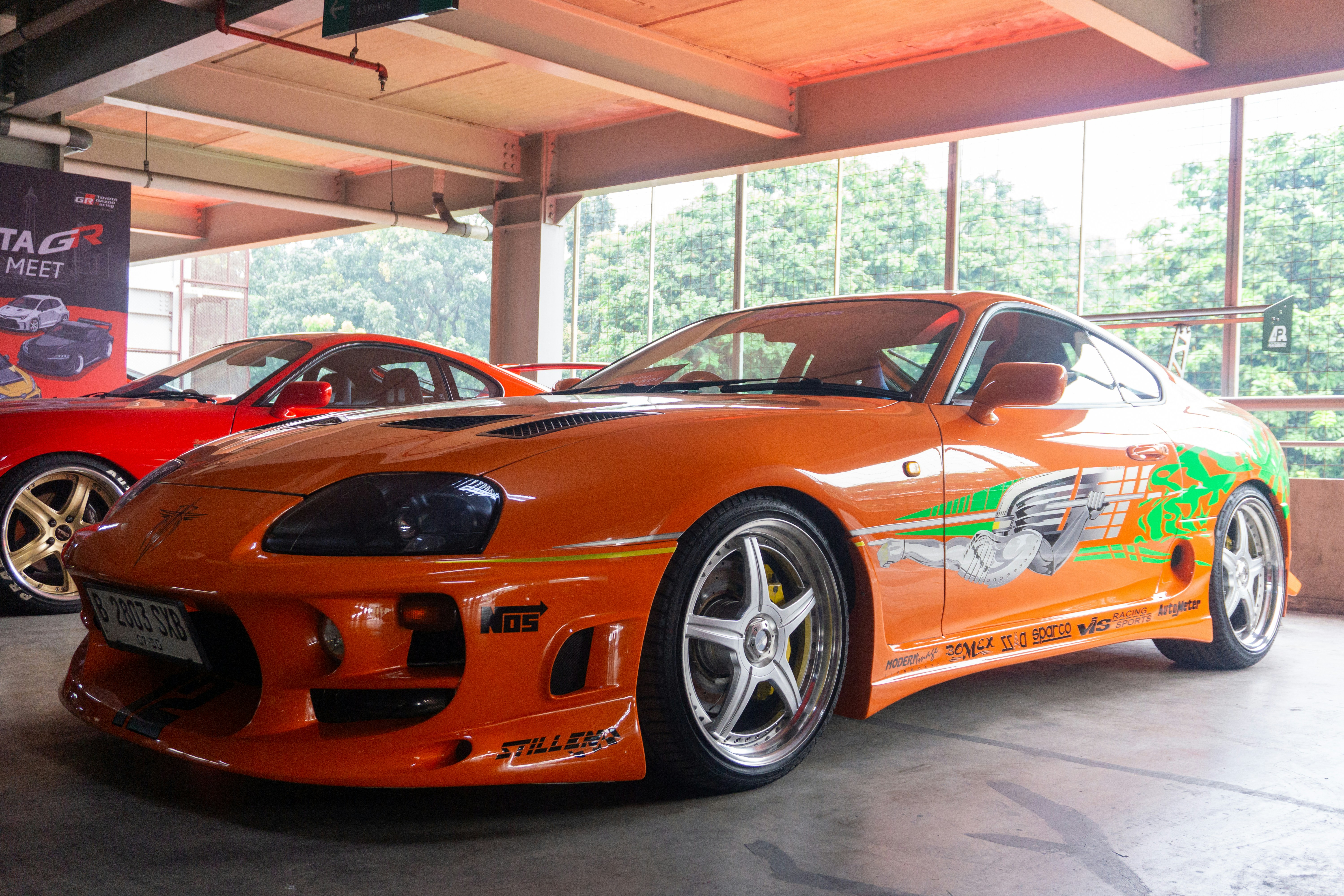 Orange race car in a showroom with neon reflections
