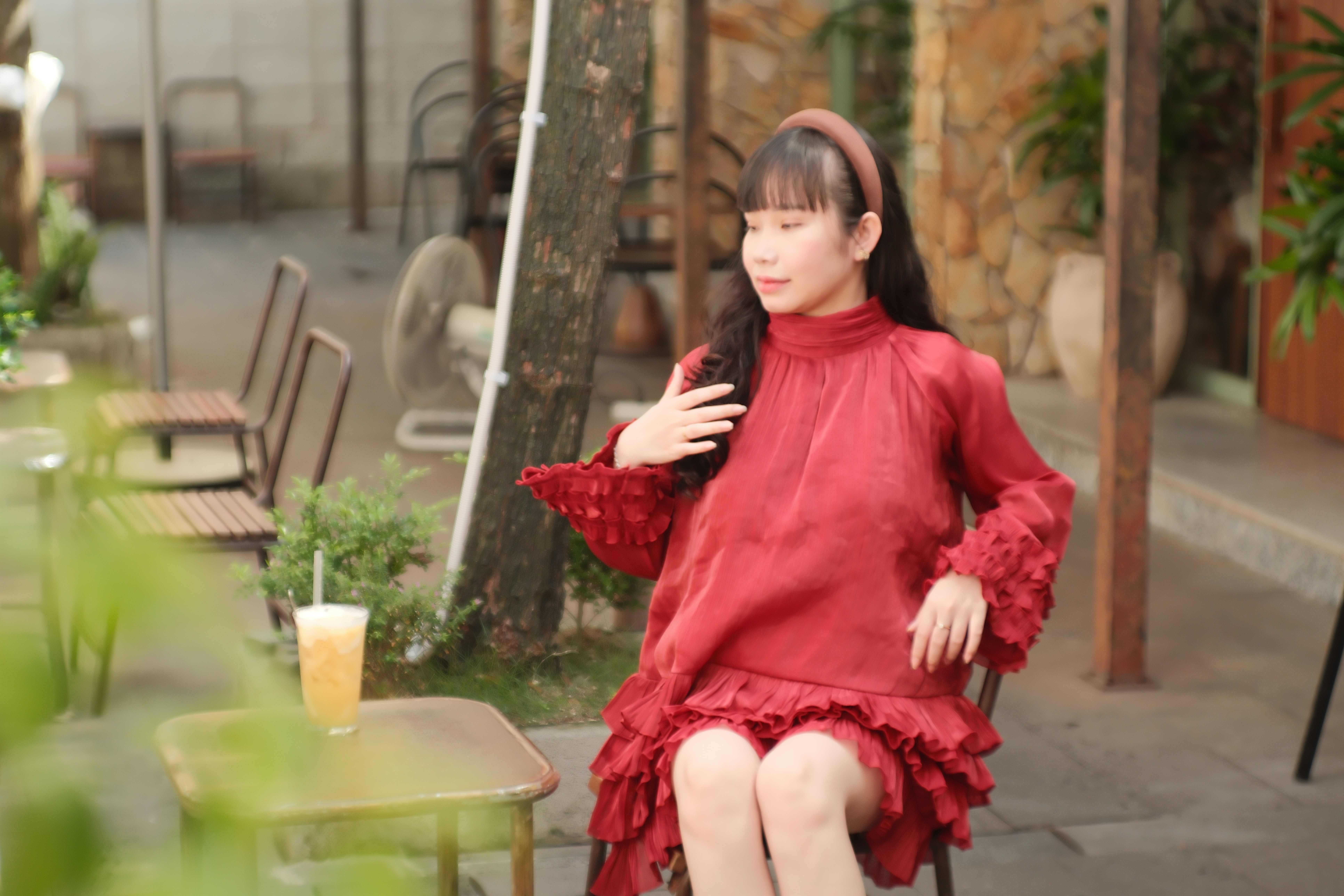 Red dress on a sunlit terrace: a candid portrait in soft focus
