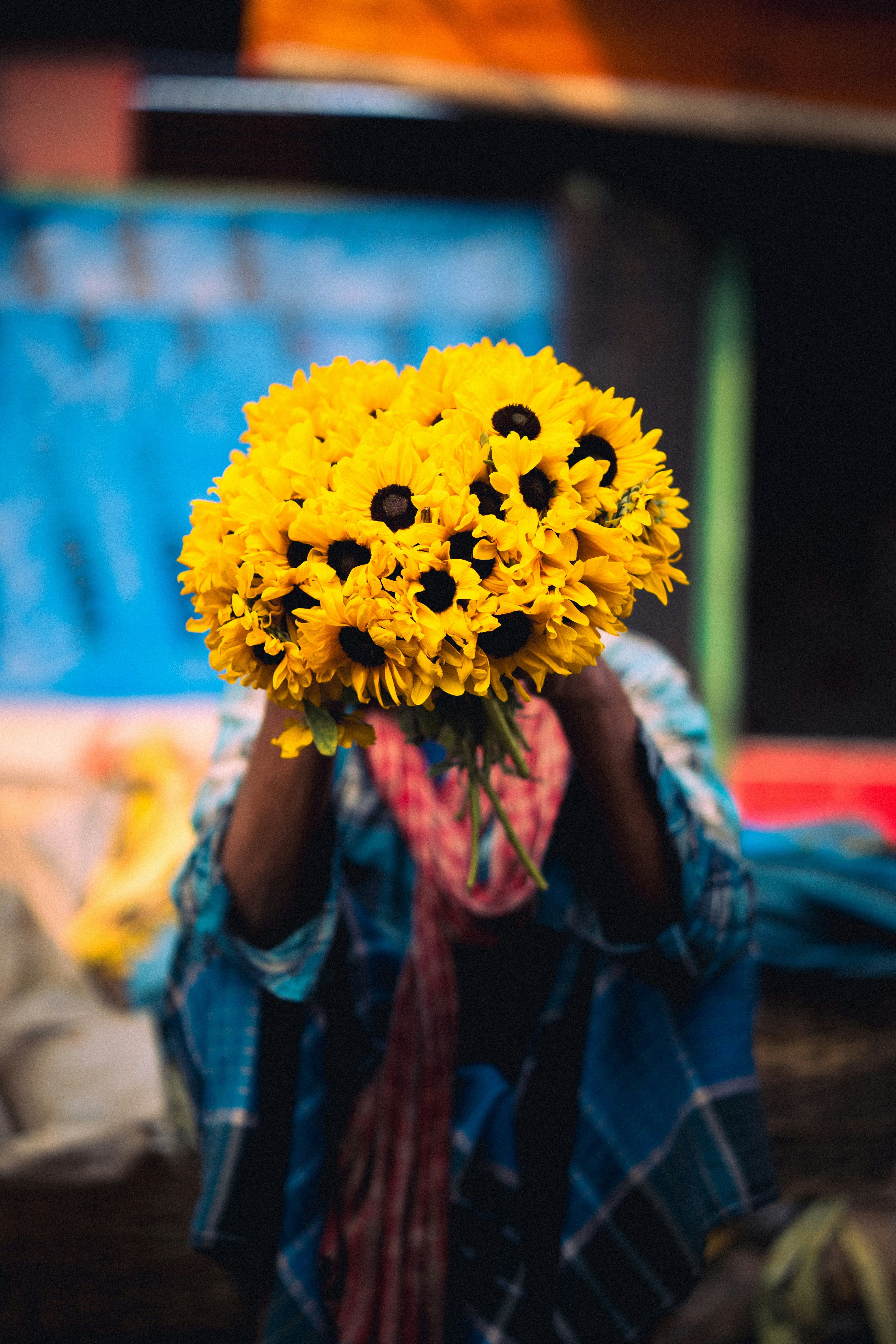 Sunlit bouquet presentation: a hand-held yellow bloom bouquet rises from beneath a plaid shawl