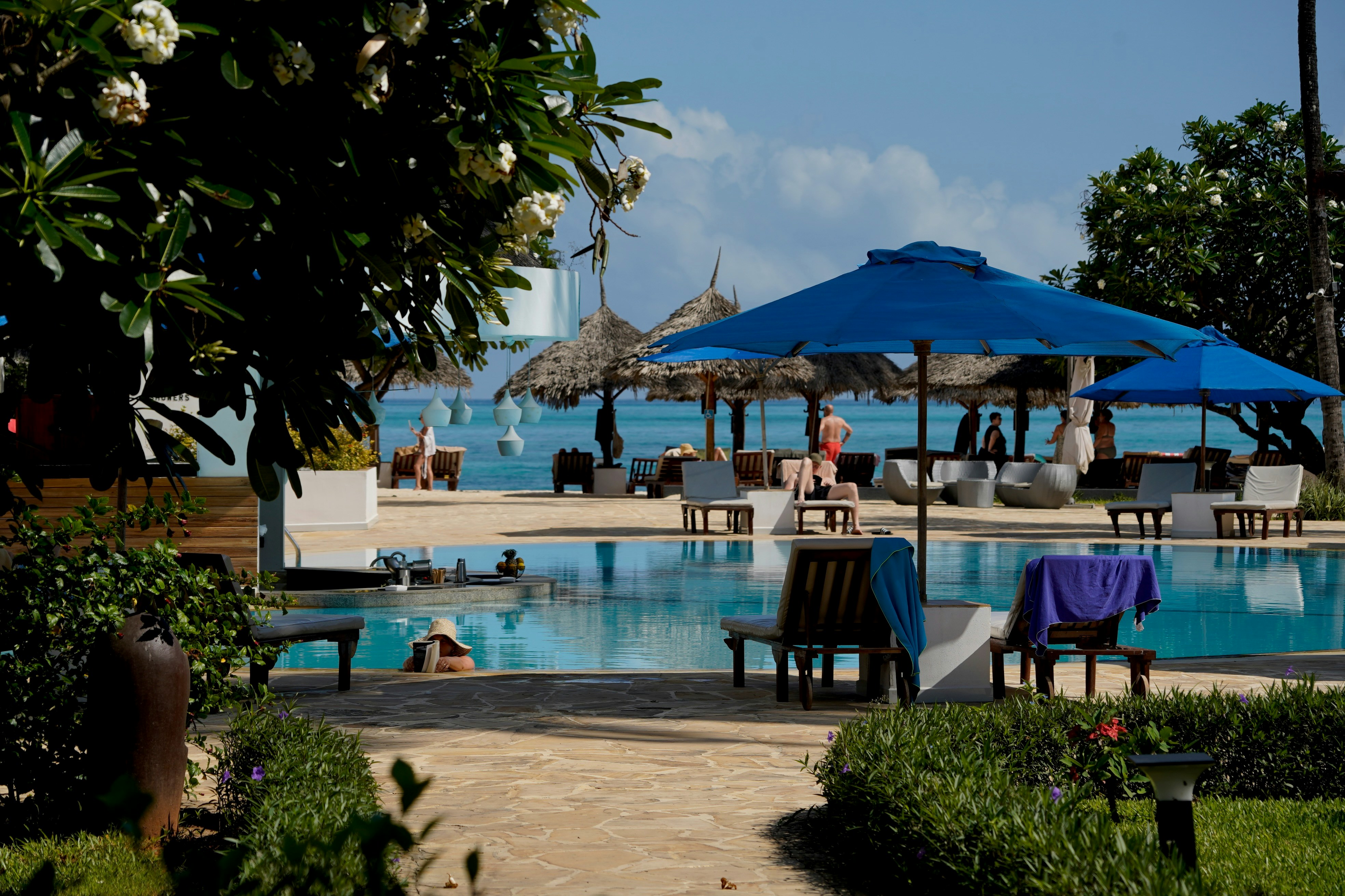 Lagoon Cooler: Sunlit Poolside Retreat with Blue Umbrellas