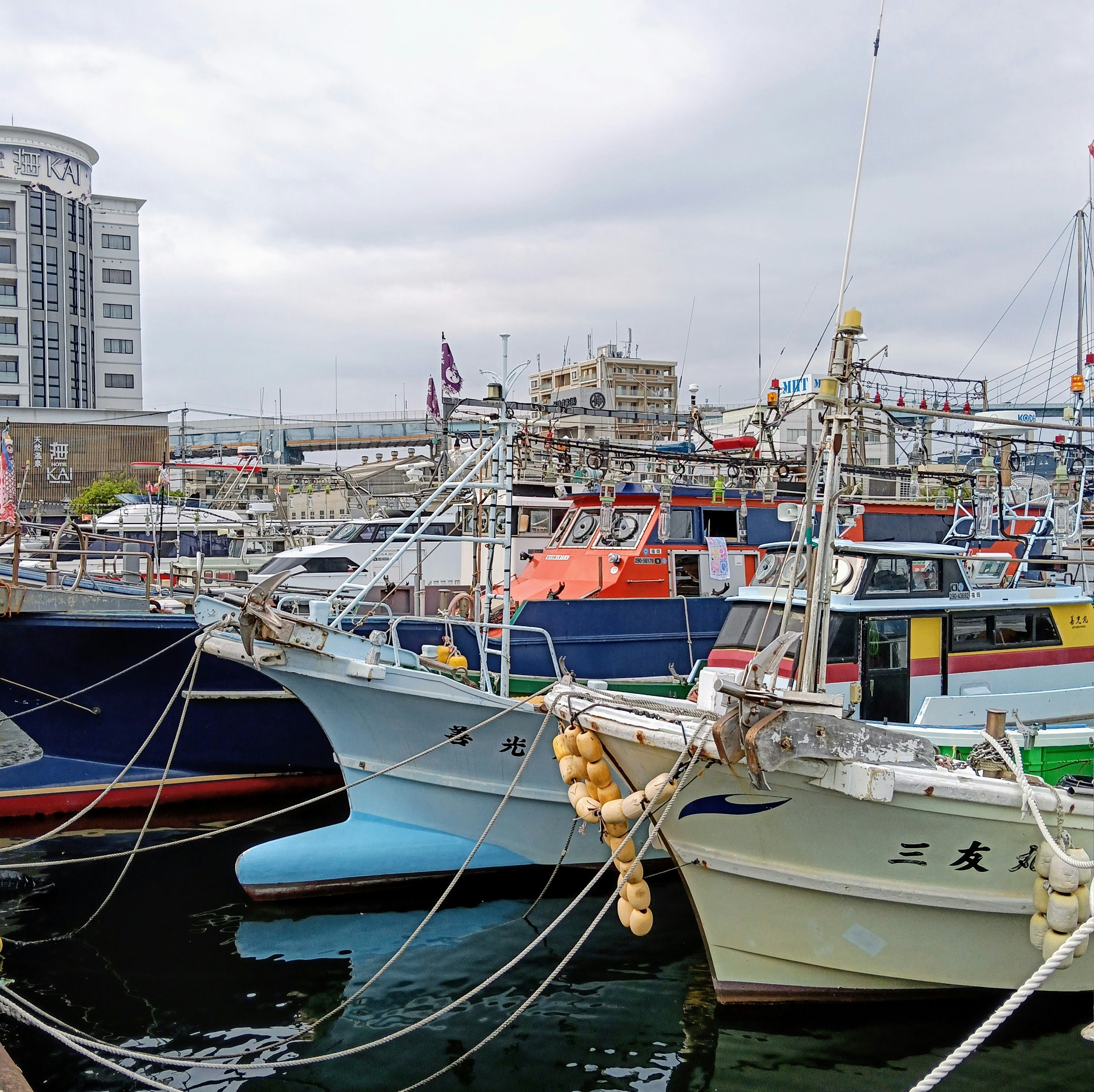 Colorful fishing boats tied at a harbor with rigging and calm water, conveying a busy port scene.