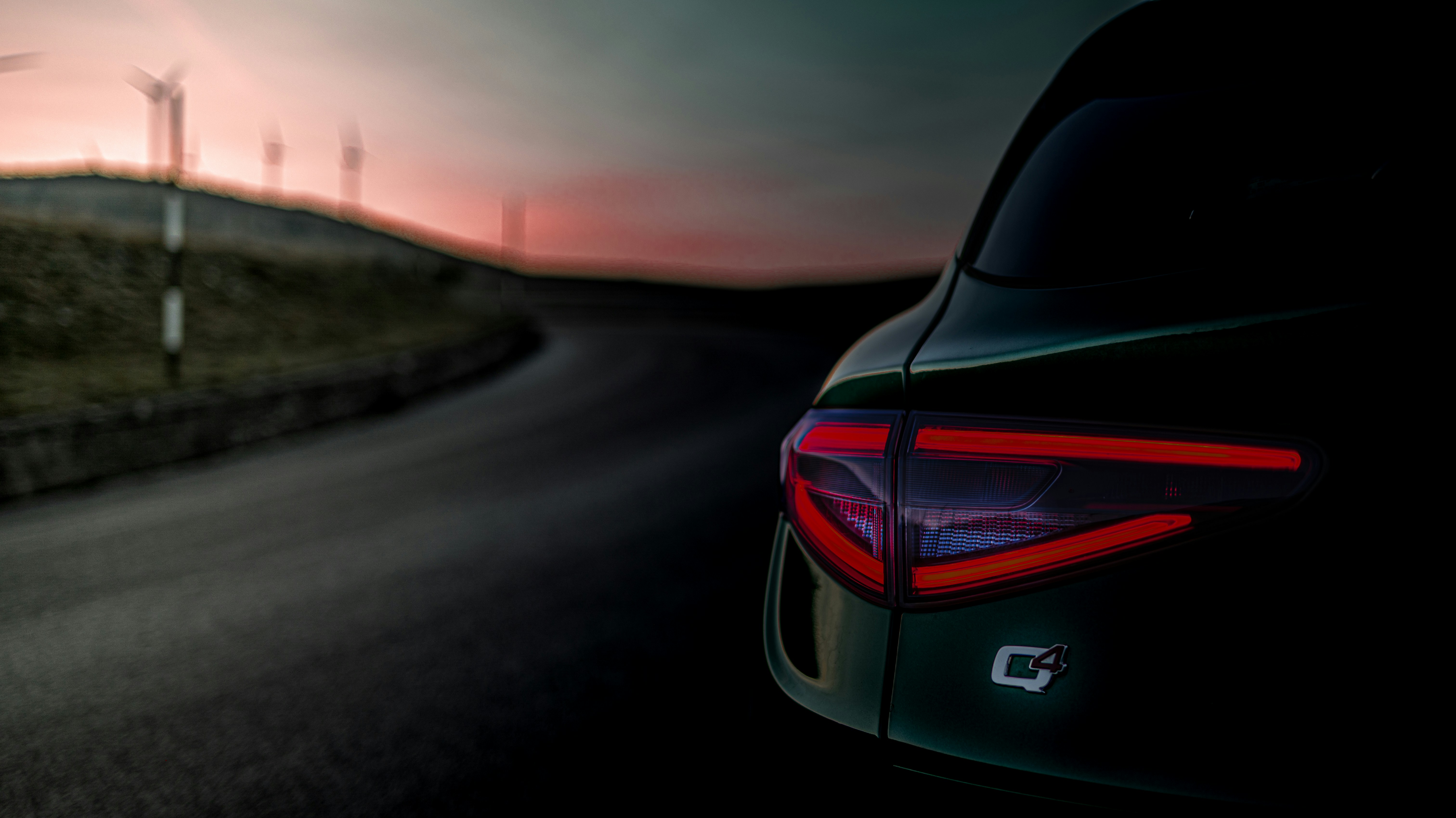 Tail Light Silhouette on a Dark Curved Road at Dusk