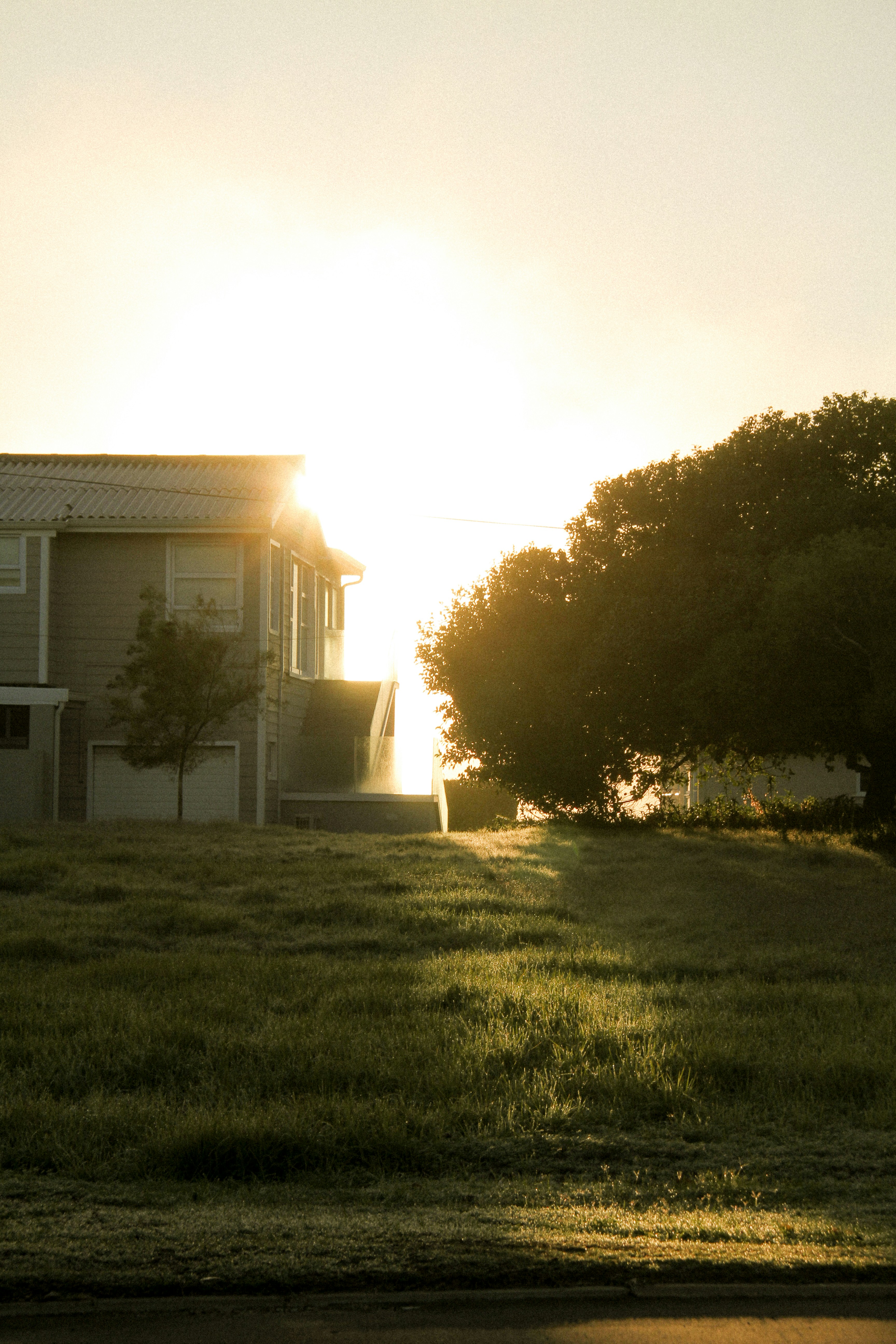 Sunlit residential stairway toward the glow beyond the house