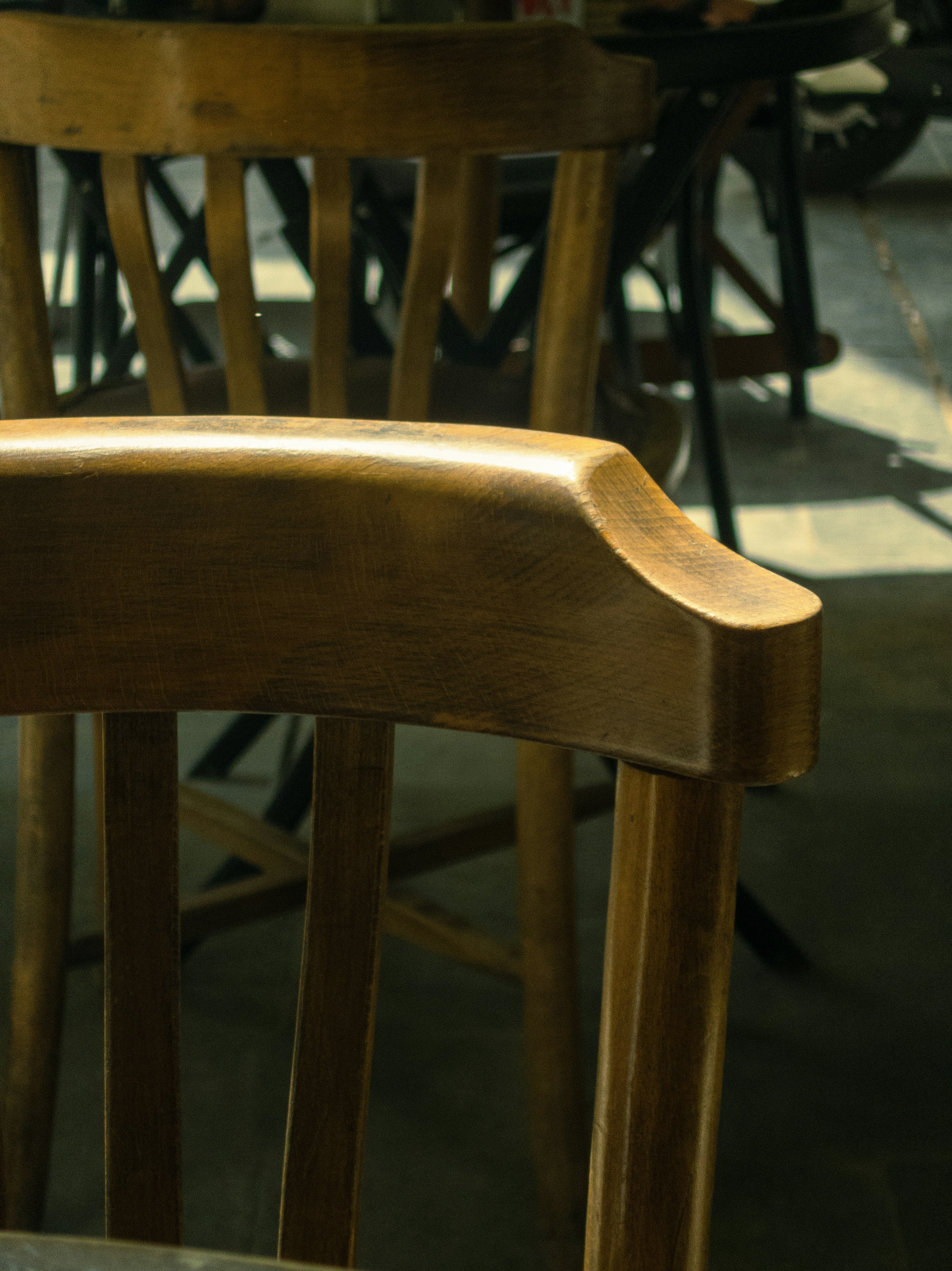 Sunlit Curve: A Close-Up of Oak Chair Arms in Quiet Café Light