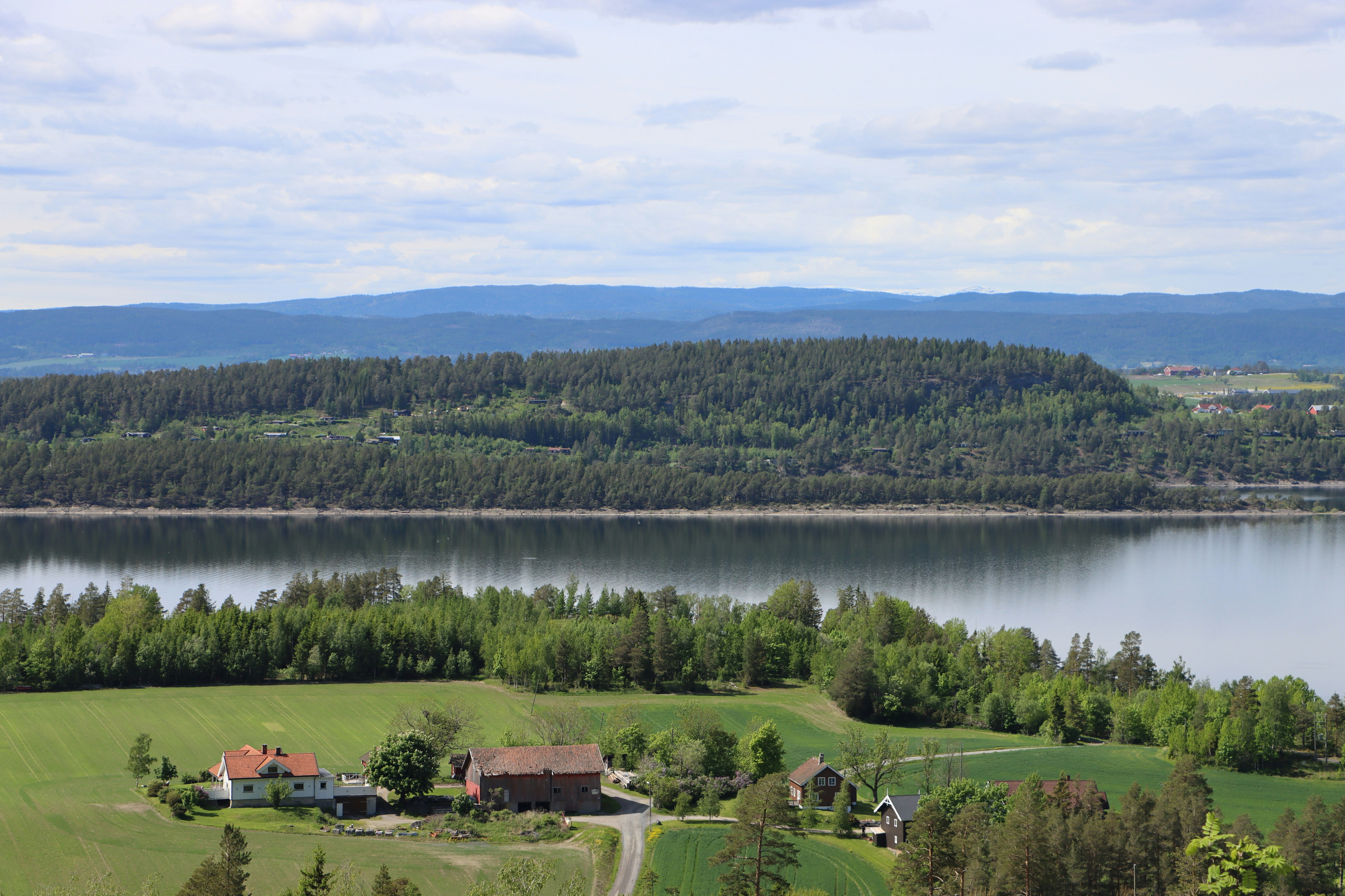 Pastoral Riverside Vista with Farmstead Under Distant Hills