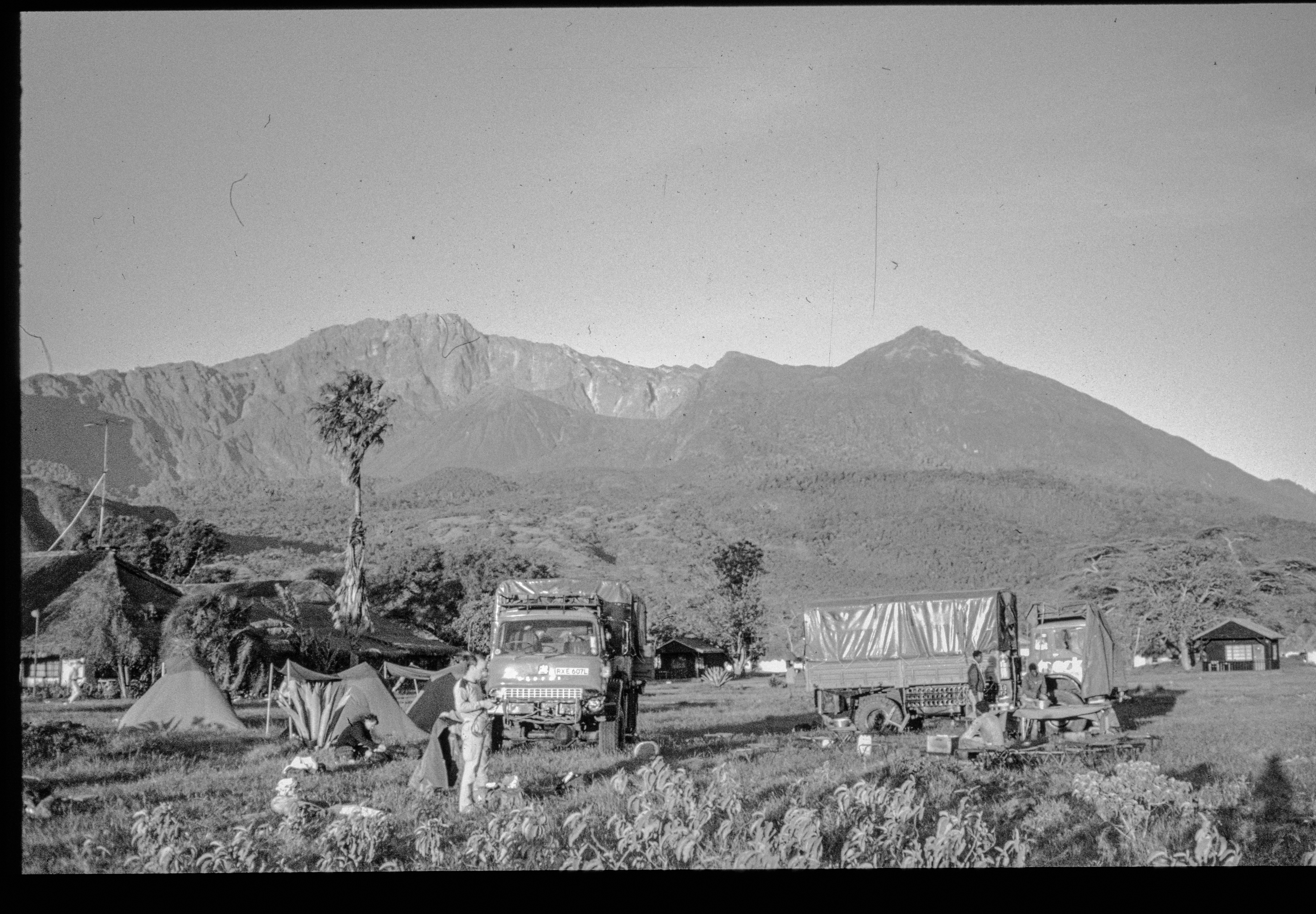 Military camp with tents and trucks in a mountainous landscape.