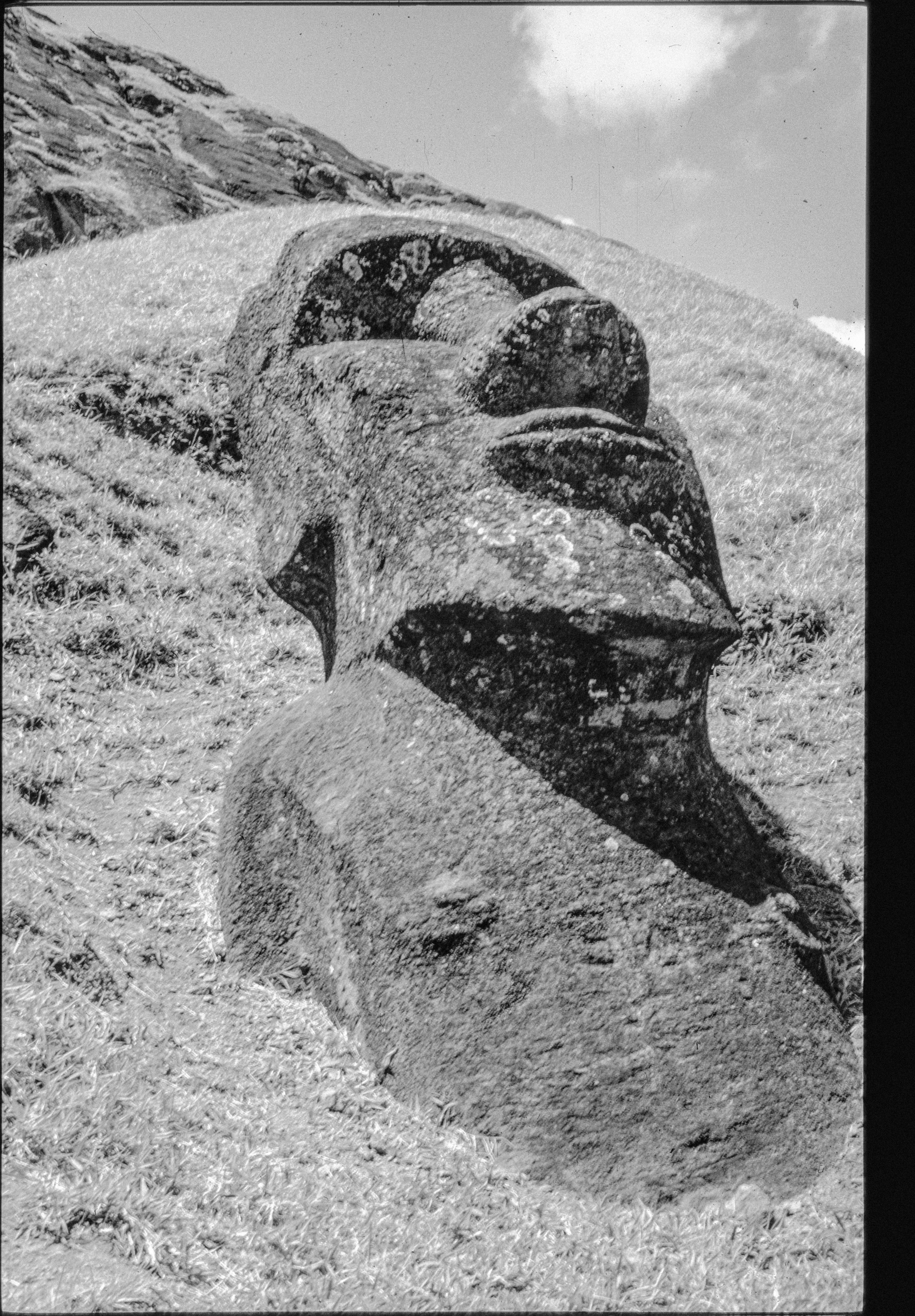 Stone Figure in Grass: An Eroded Carved Form Beneath Open Sky