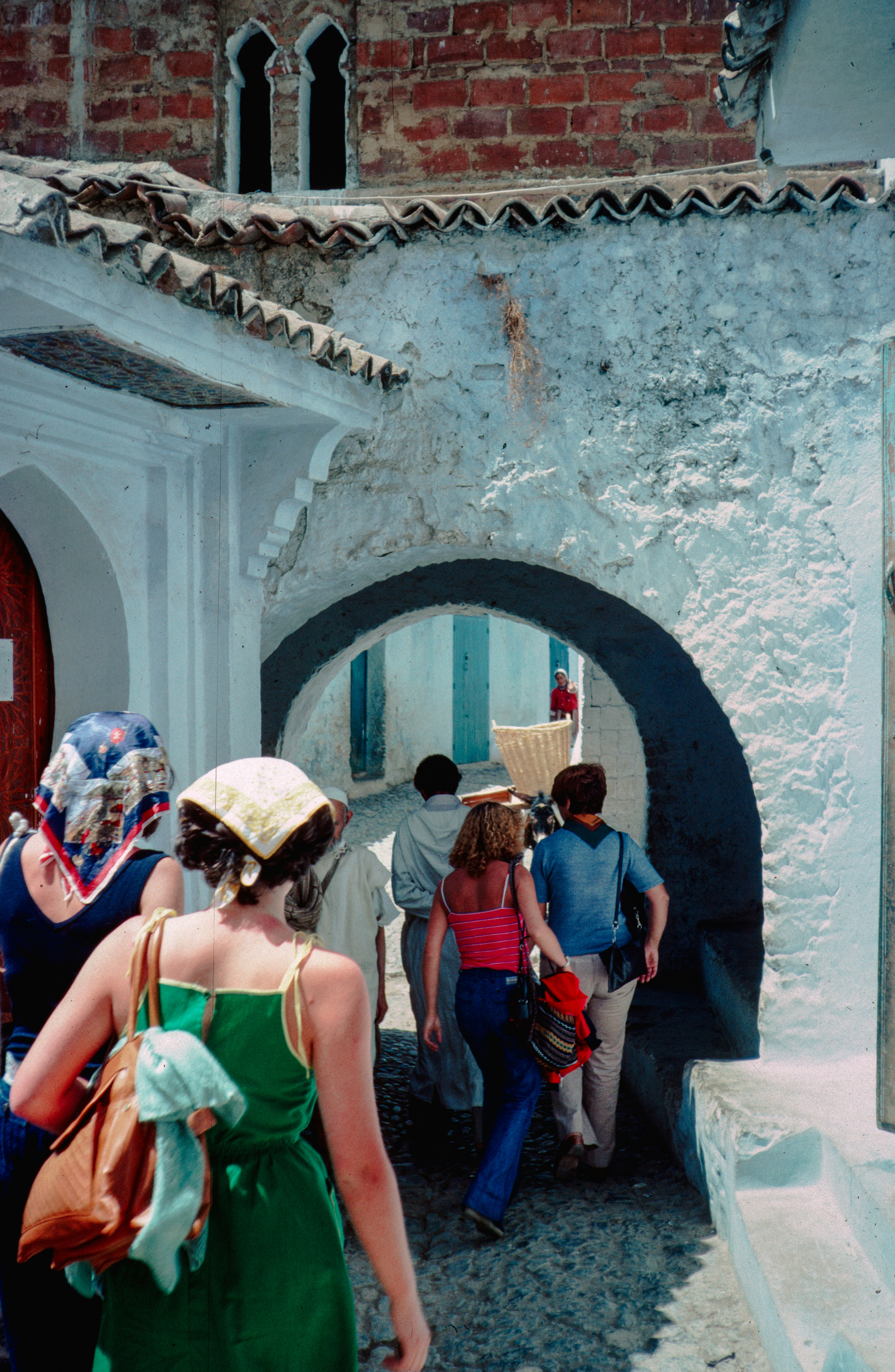 People Thread the Arched Gateway into a Sunlit Courtyard