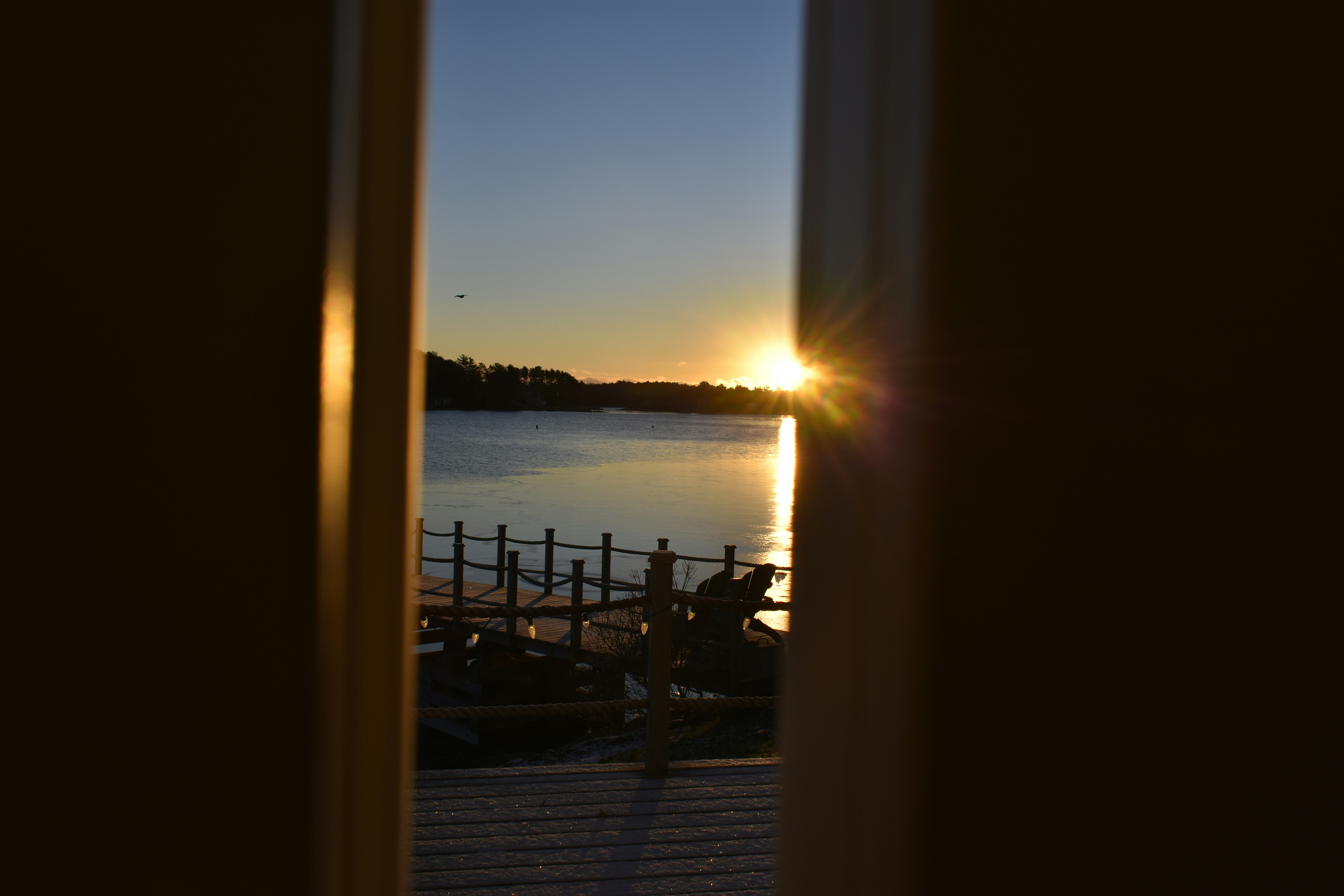 Golden sunset over a calm lake framed by a doorway.