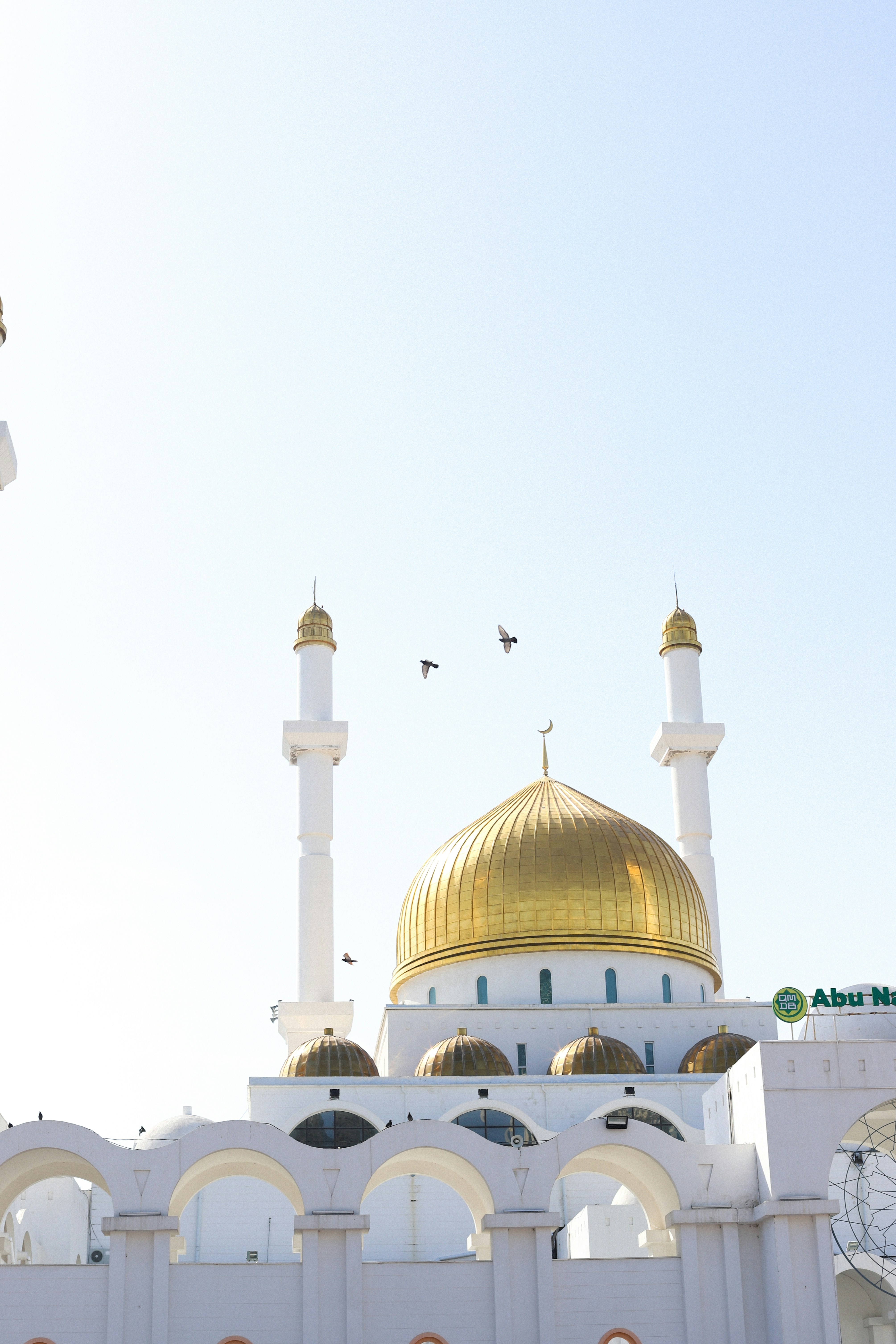 Gold Dome Over White Arches: A Mosque Under a Bright Sky
