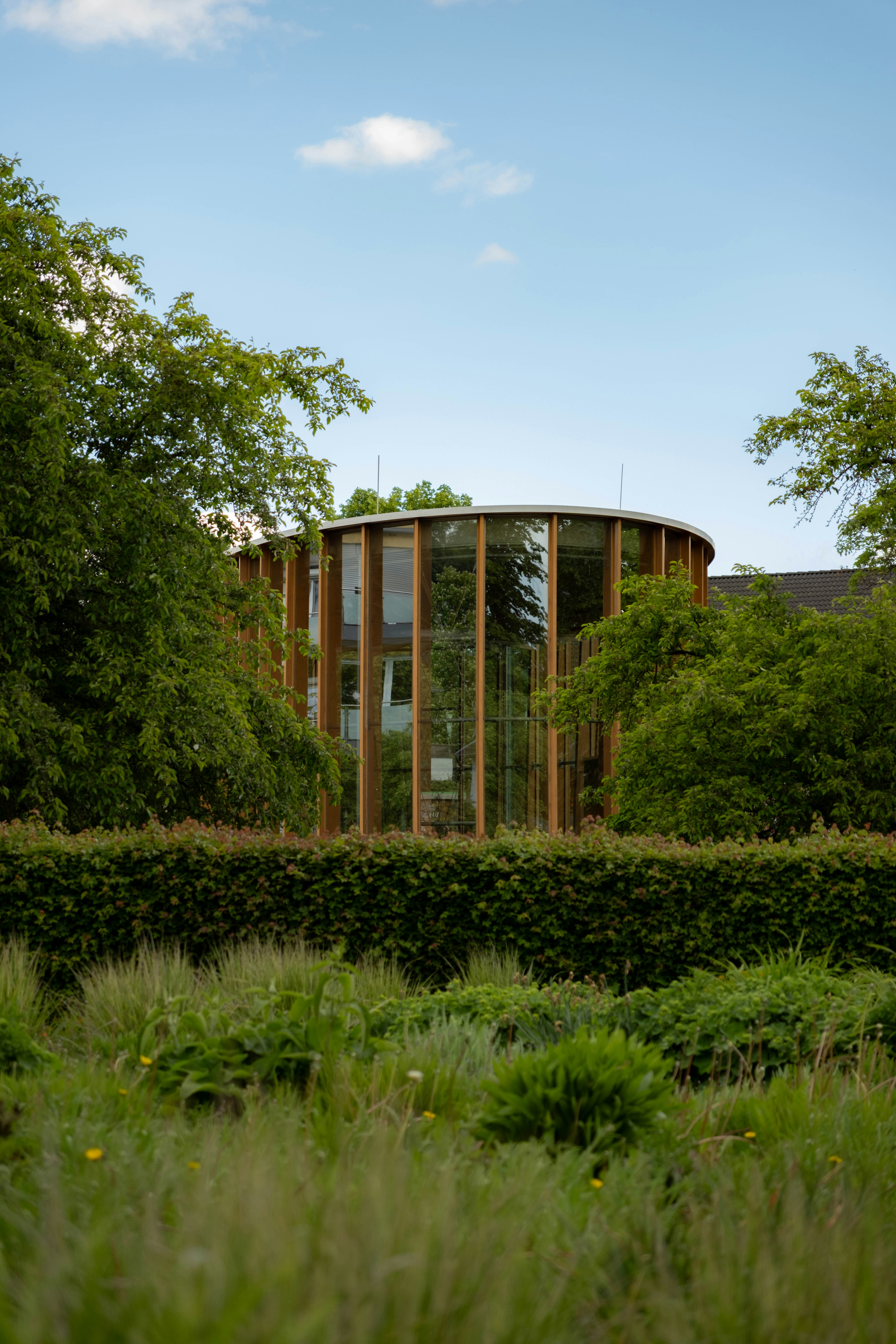 Circular glass pavilion framed by lush greenery