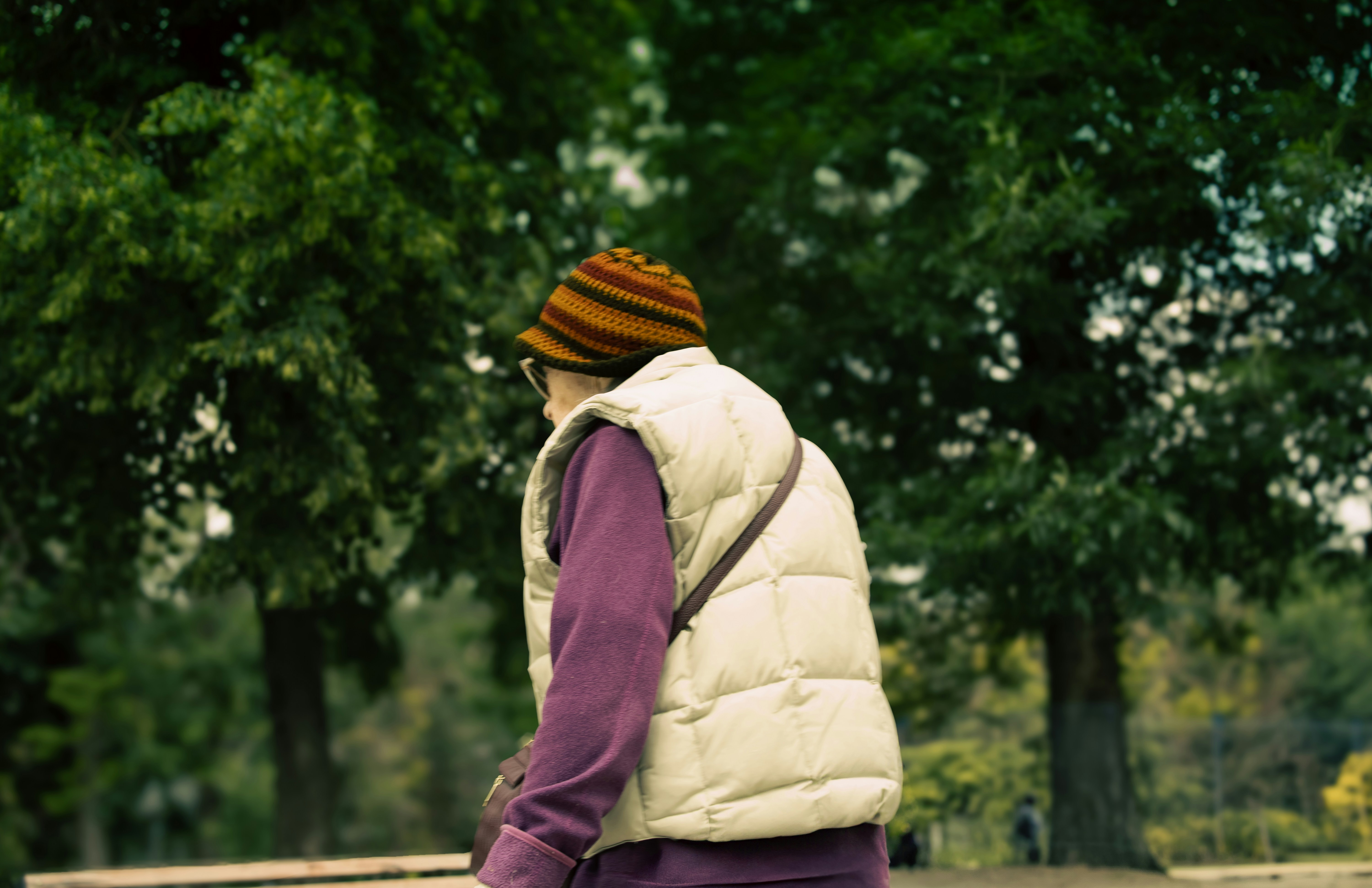 The Quiet Stroll: Elder in a Puffy Vest Amid Urban Green