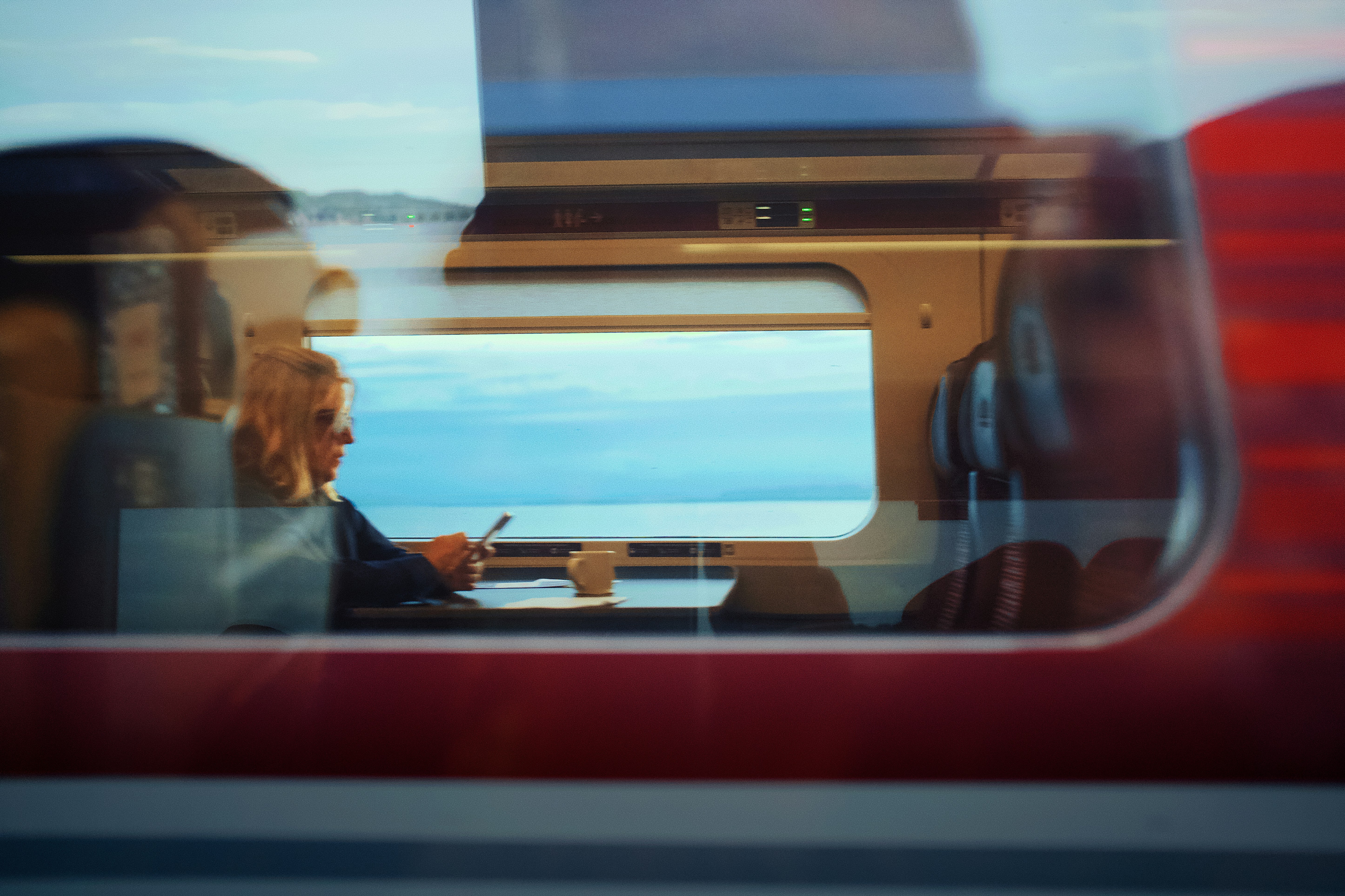 Window Seat Reflections: Passenger with Tablet Inside a Train