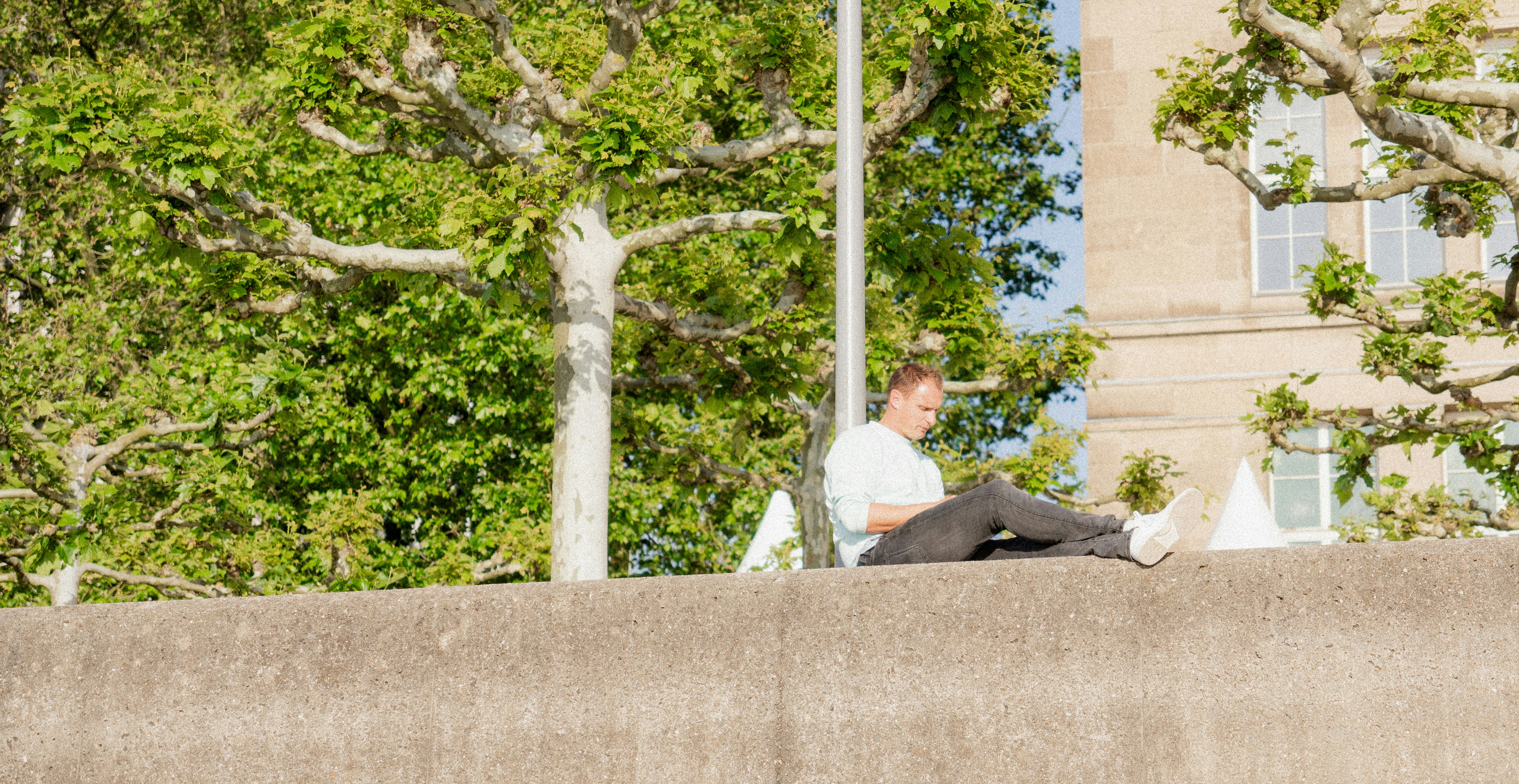 A quiet moment atop the steps: reader in the sun near a city courtyard