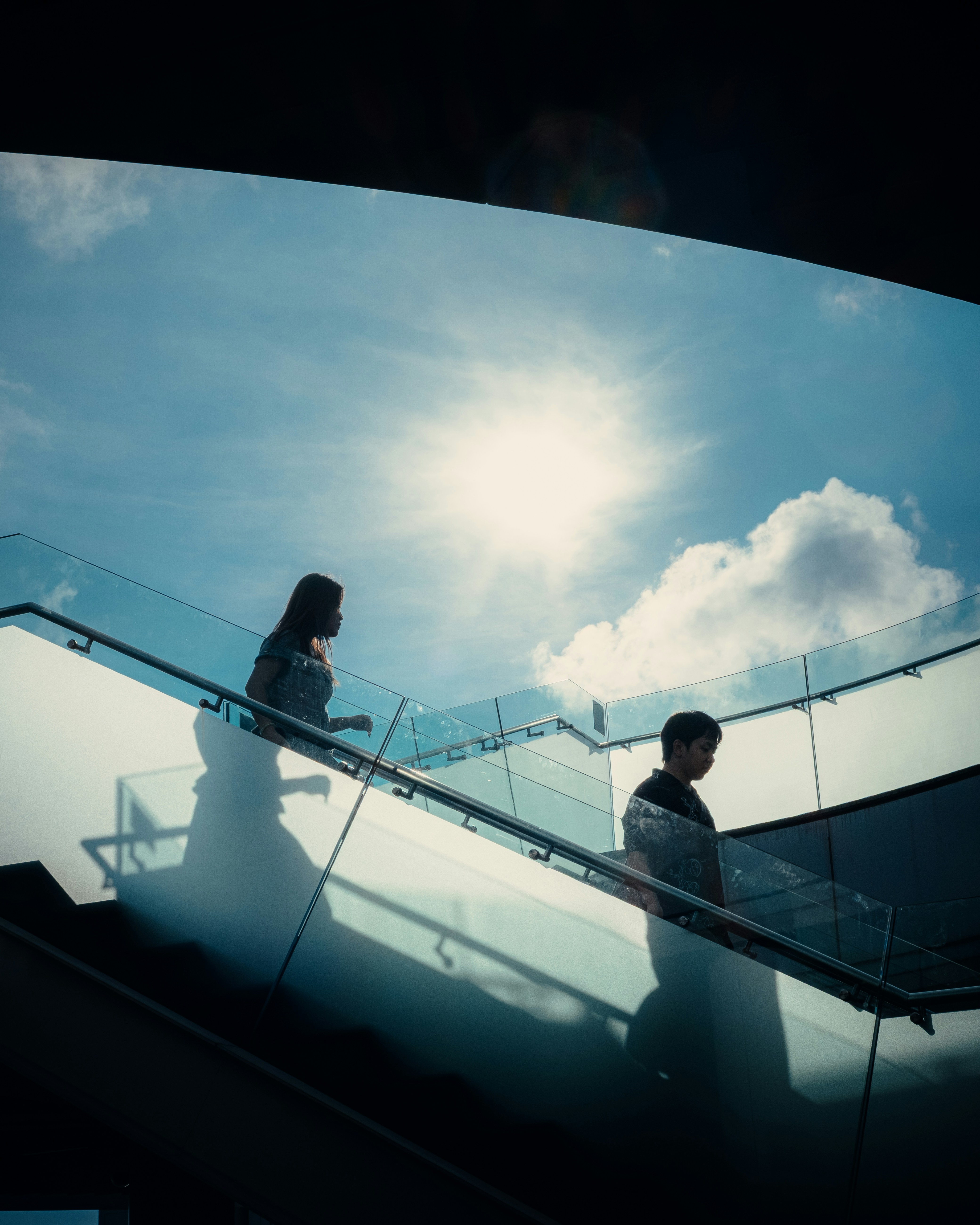 Two silhouettes on a glass-rail skyward ascent