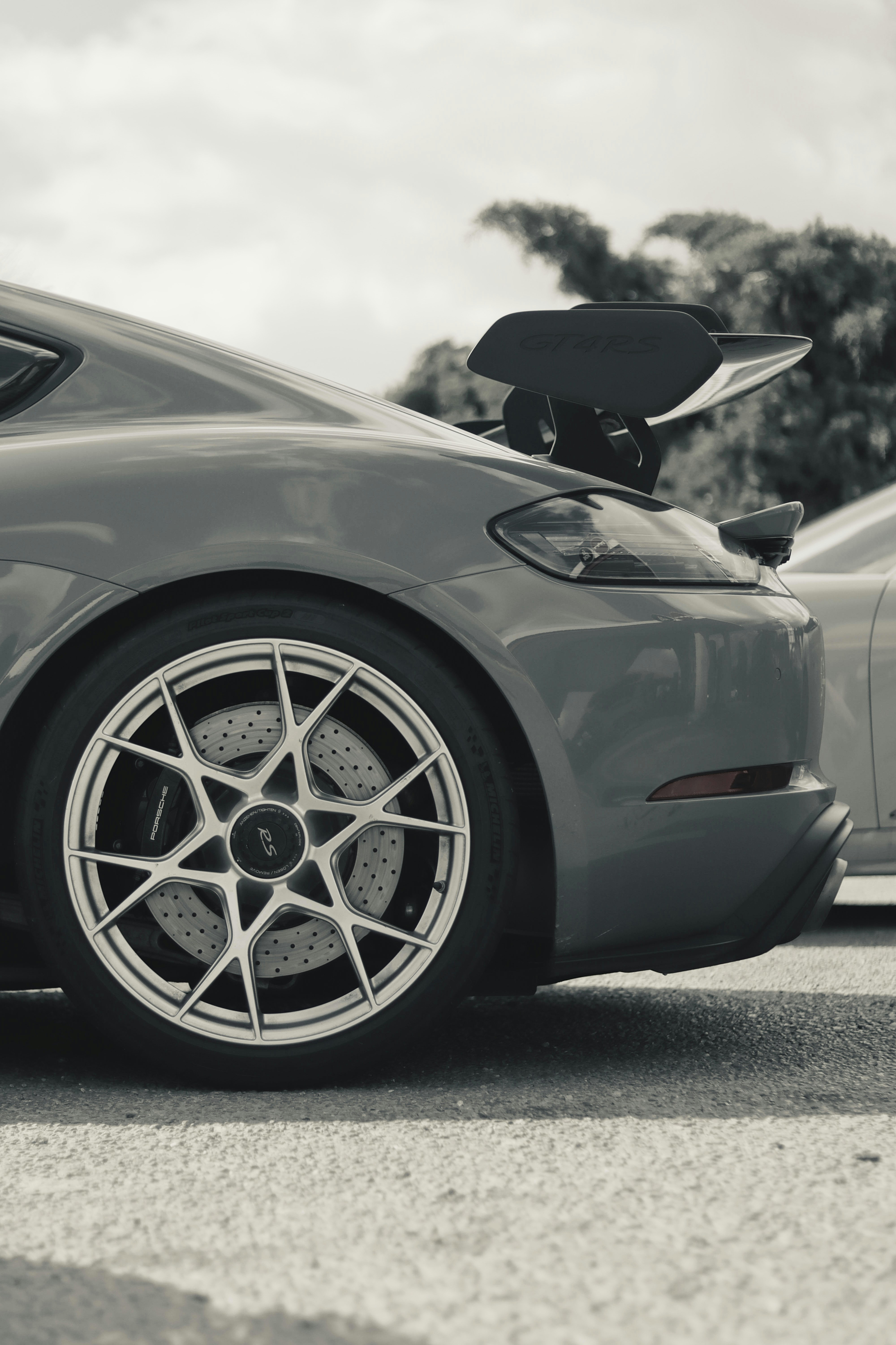 Grey sports car with prominent rear spoiler and detailed wheel.