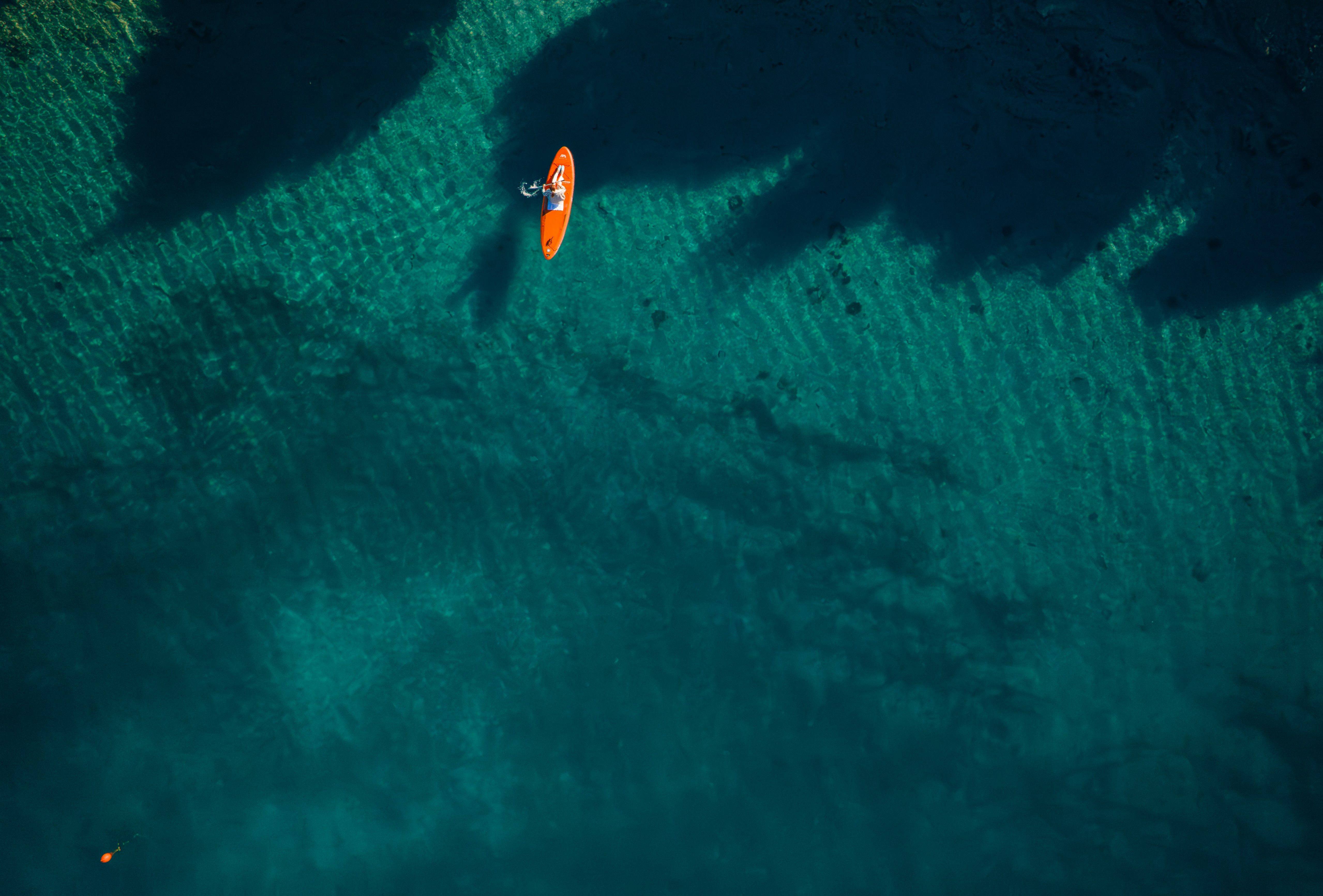 Orange Paddleboarder in Turquoise Sea: An Aerial Moment