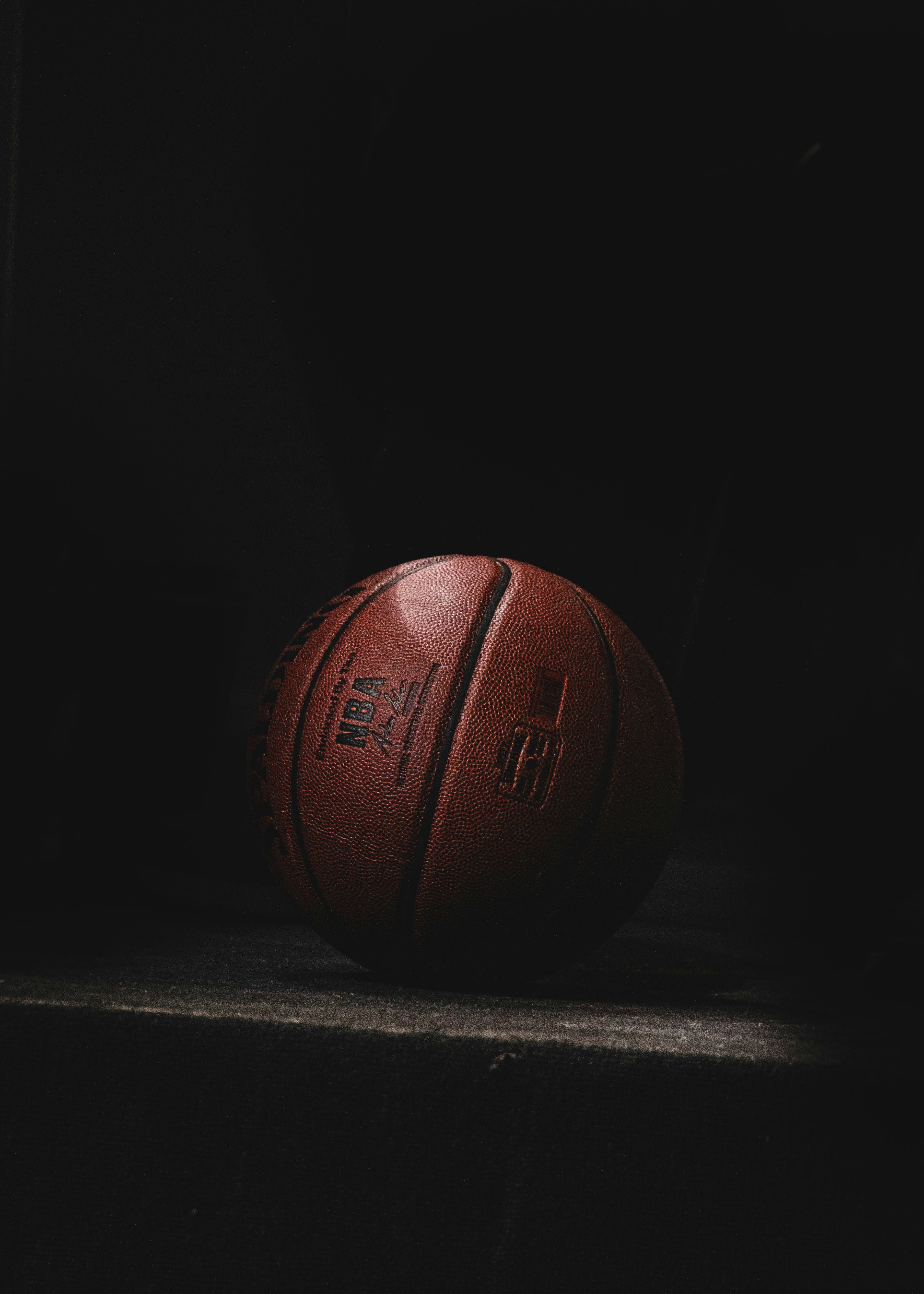 Dimly Lit Basketball: A Lone Ball Resting in Shadowed Spotlight