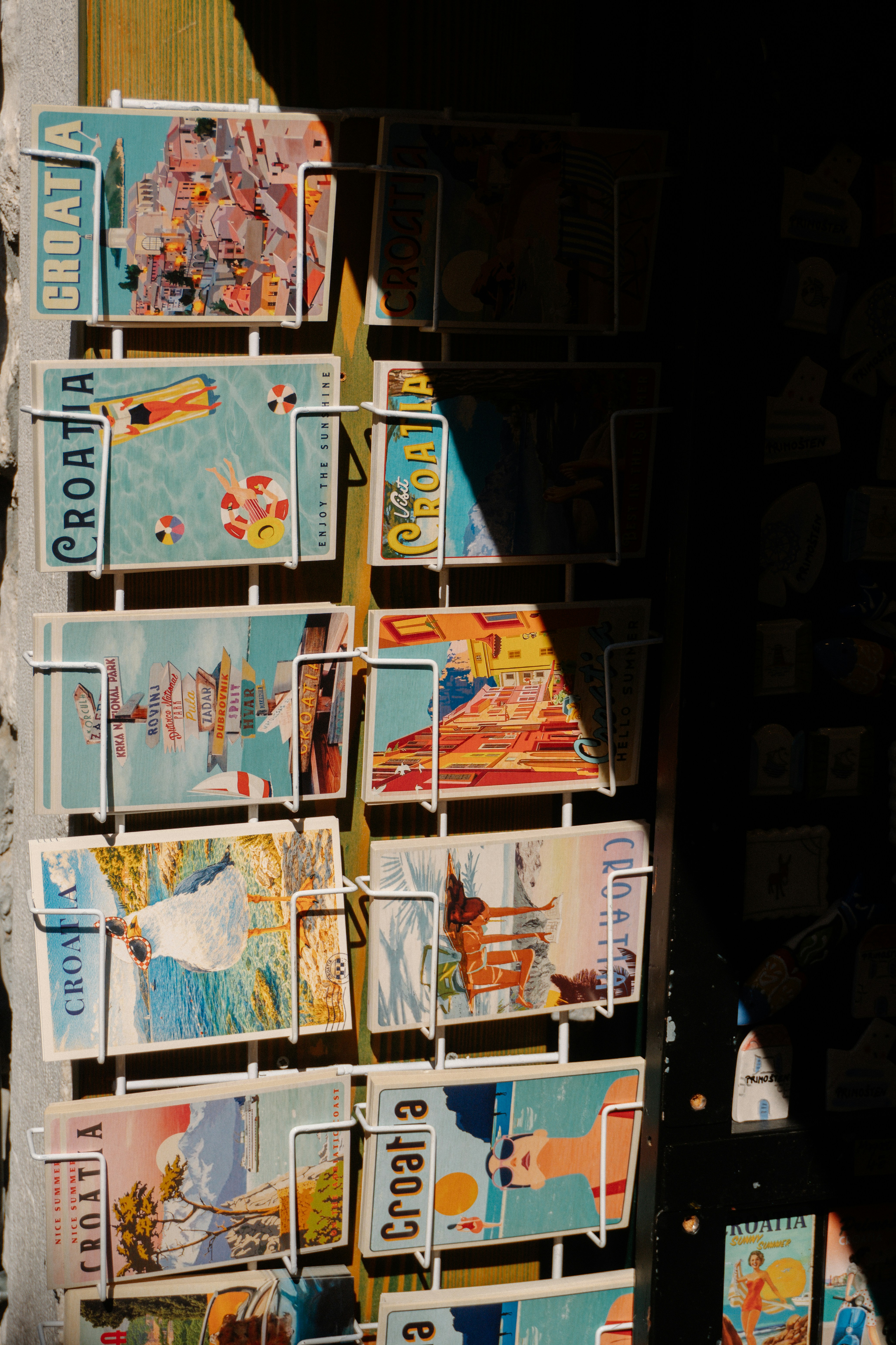 Shoreline of Vintage Travel: A Rack of Retro Postcards in Sunlit Shadow