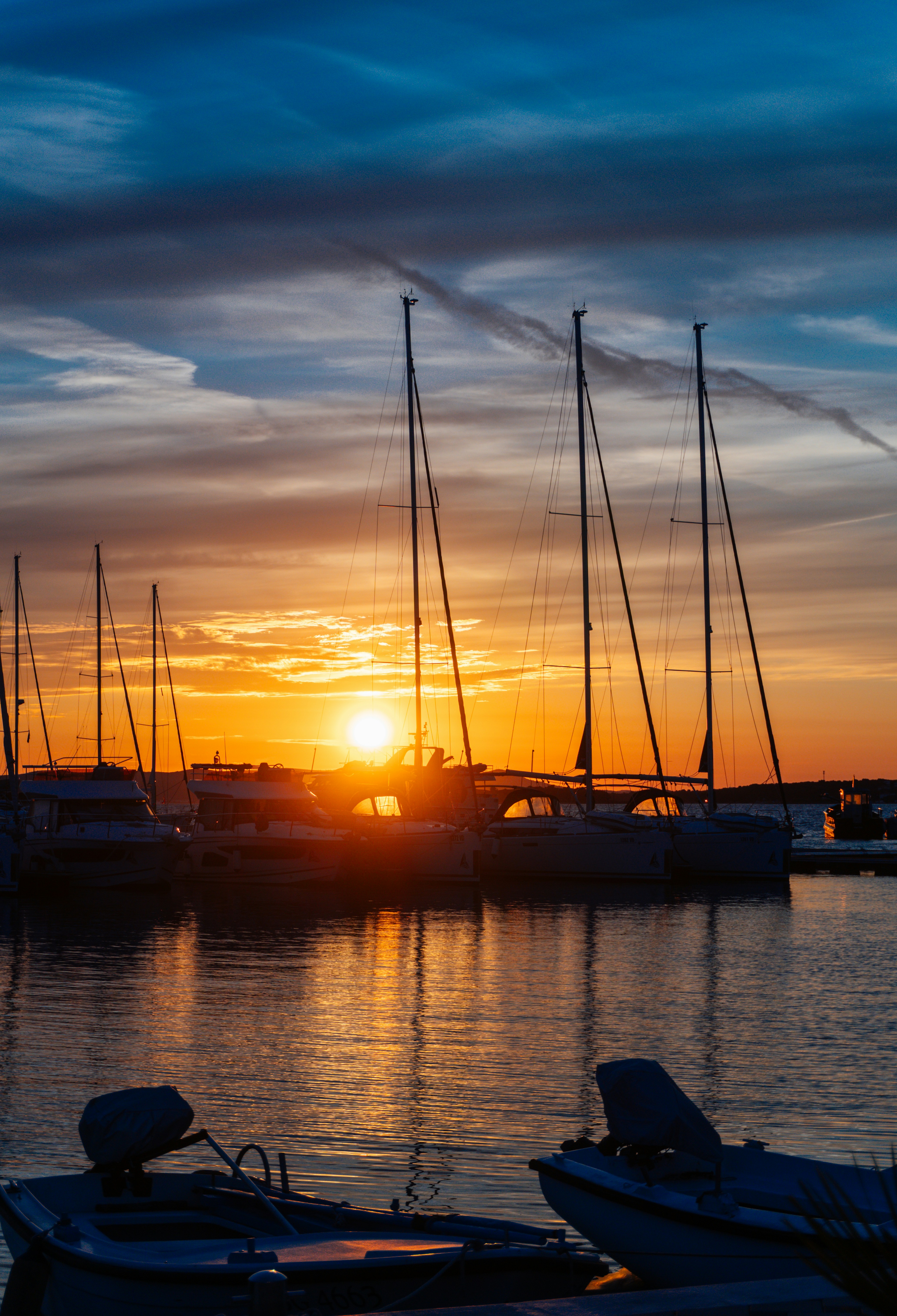 Sunlit Docks at Dusk: Boats Silhouetted as the Horizon Holds Fire