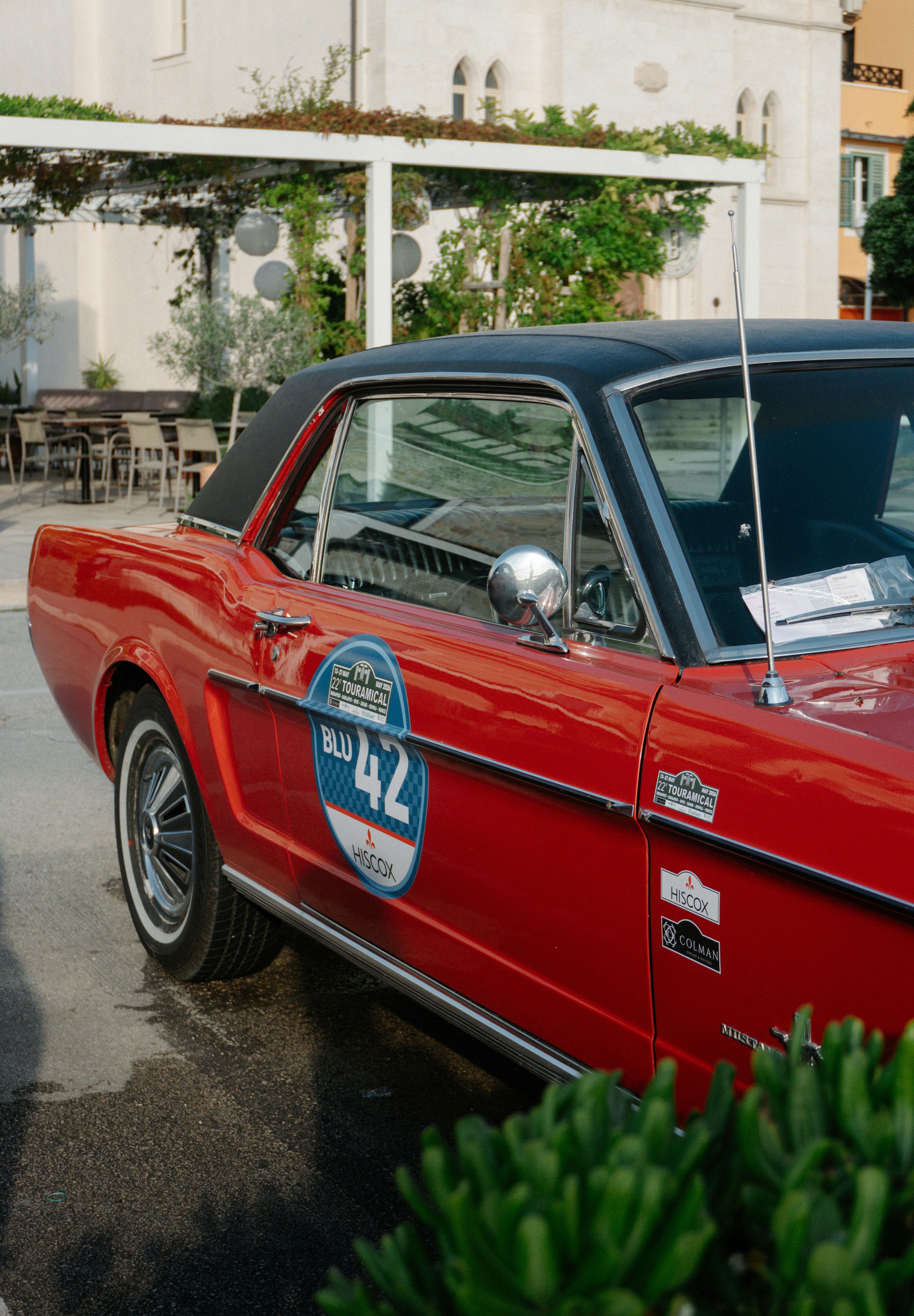 Vintage Red Muscle Car Pausing by a Café Corner