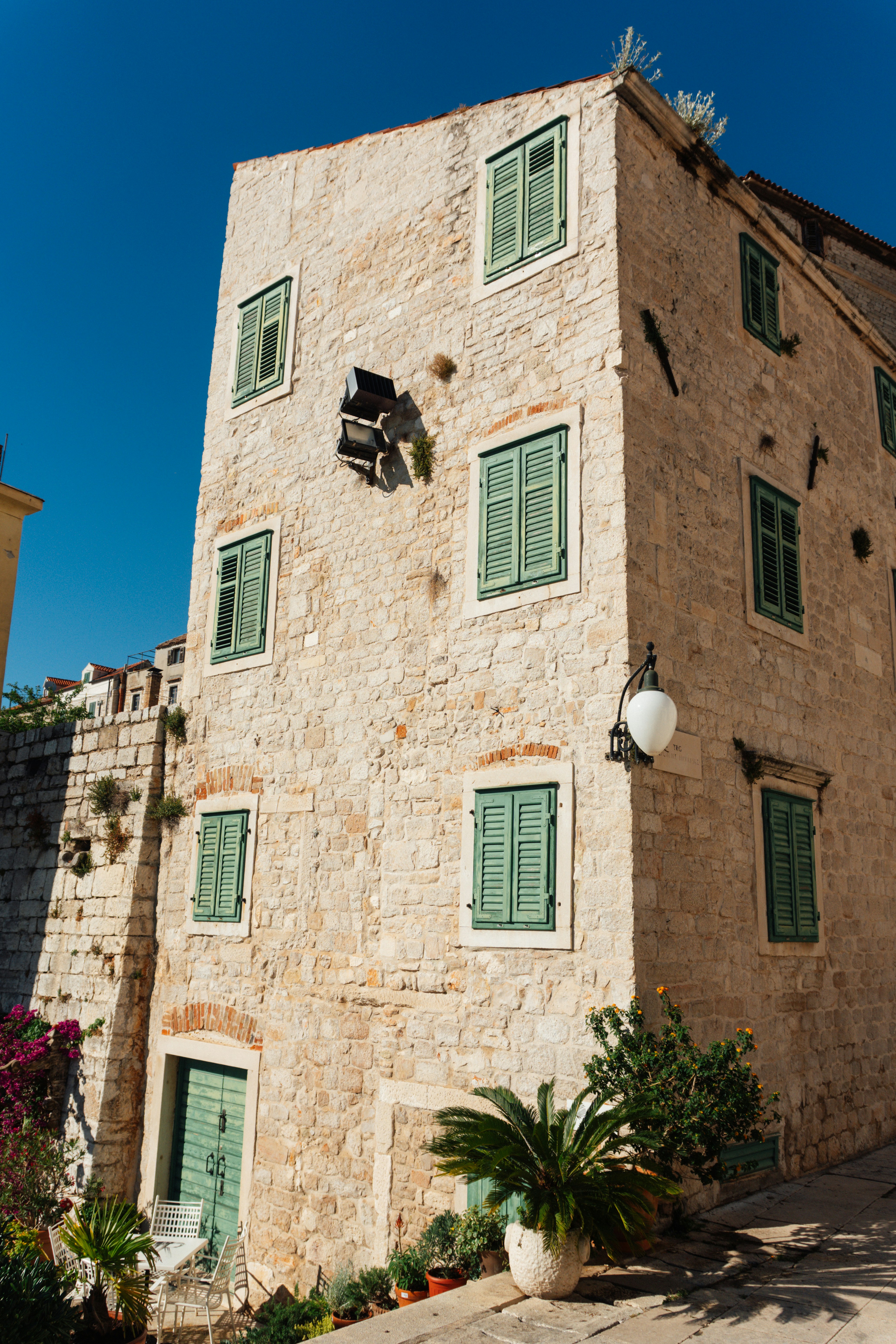 Stone House with Green Shutters on a Sunny Mediterranean Street