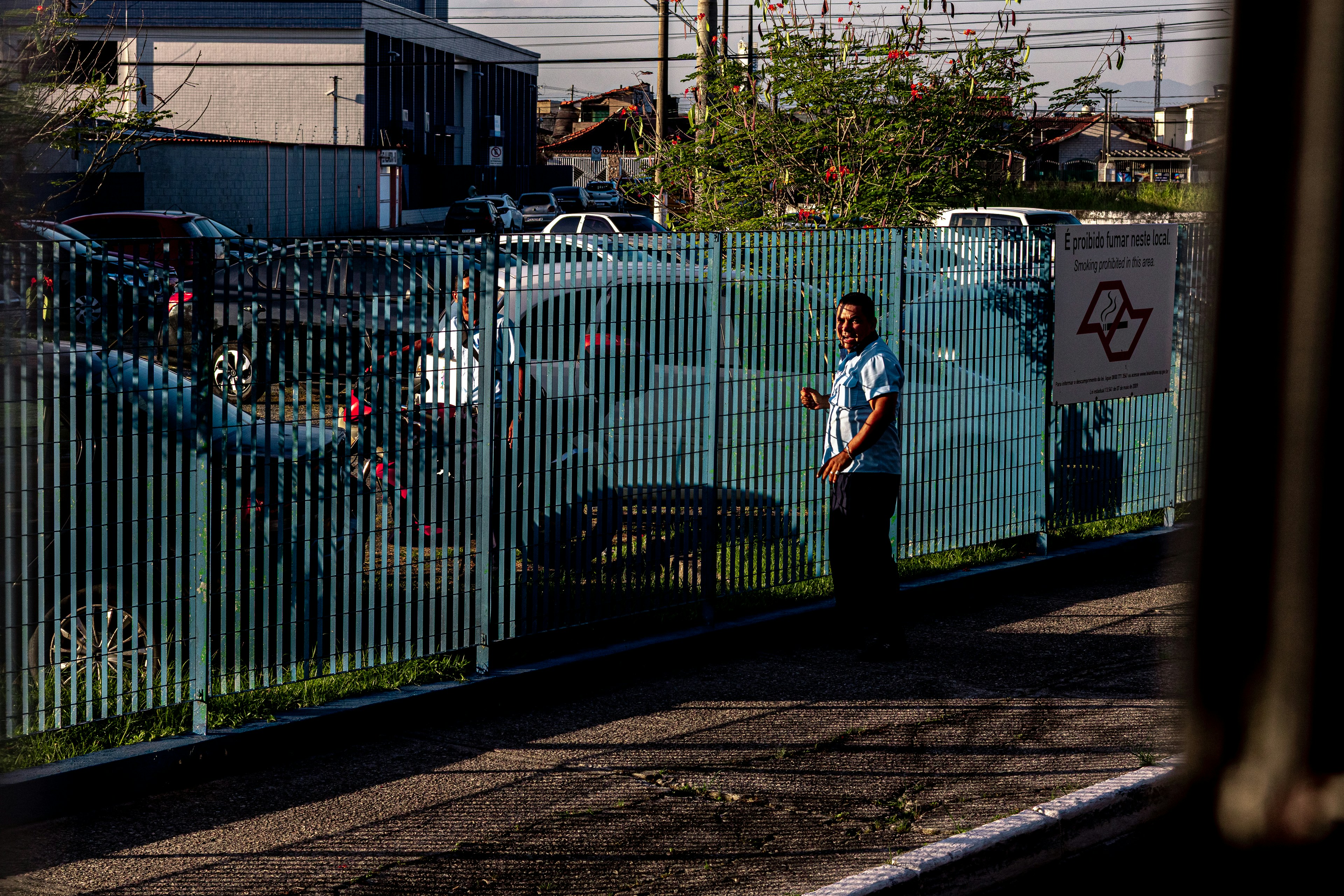 Fence-line Portrait: A Man Pausing at the Perimeter