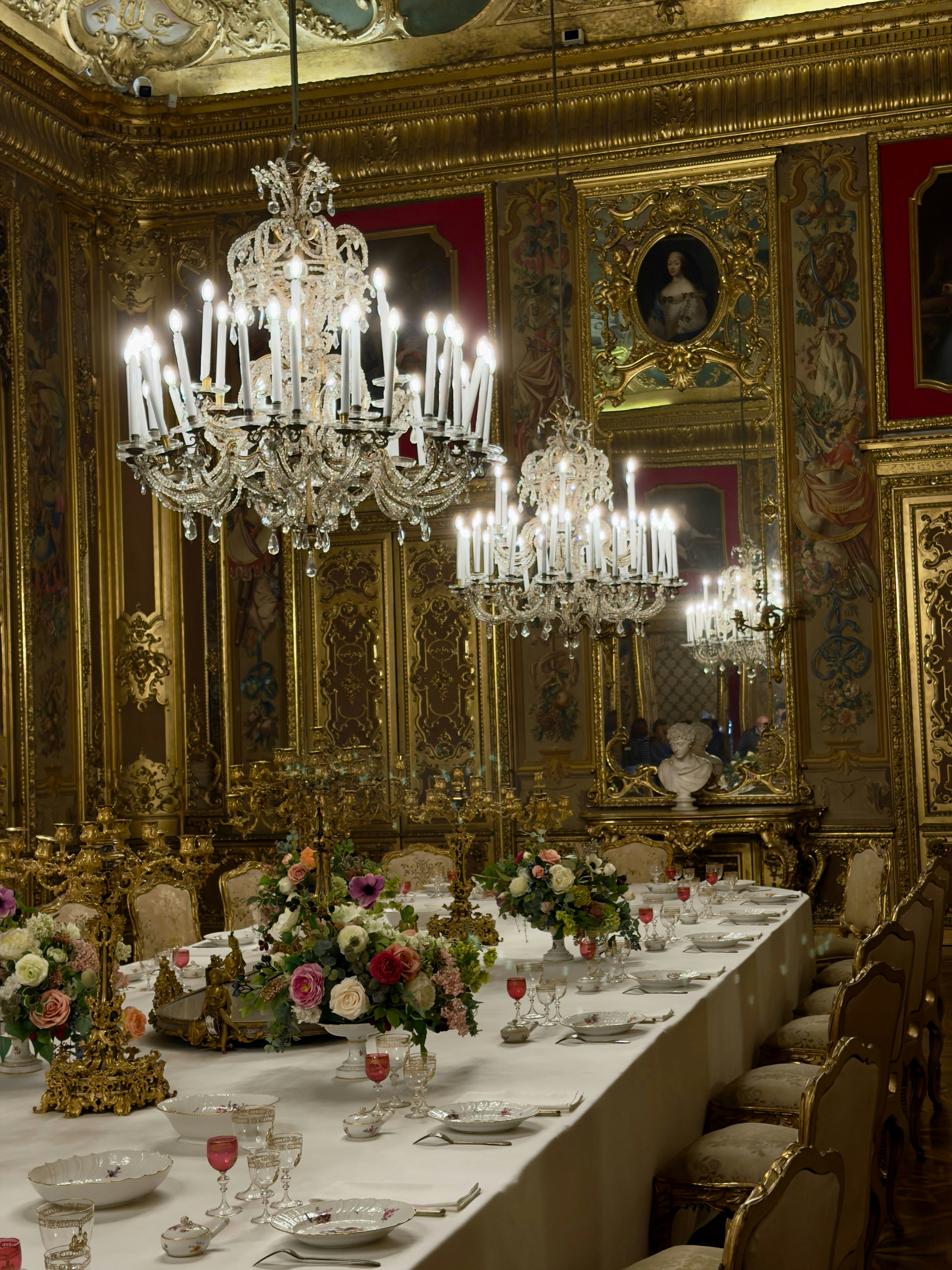 Lavish dining room with ornate gold decor and crystal chandeliers.