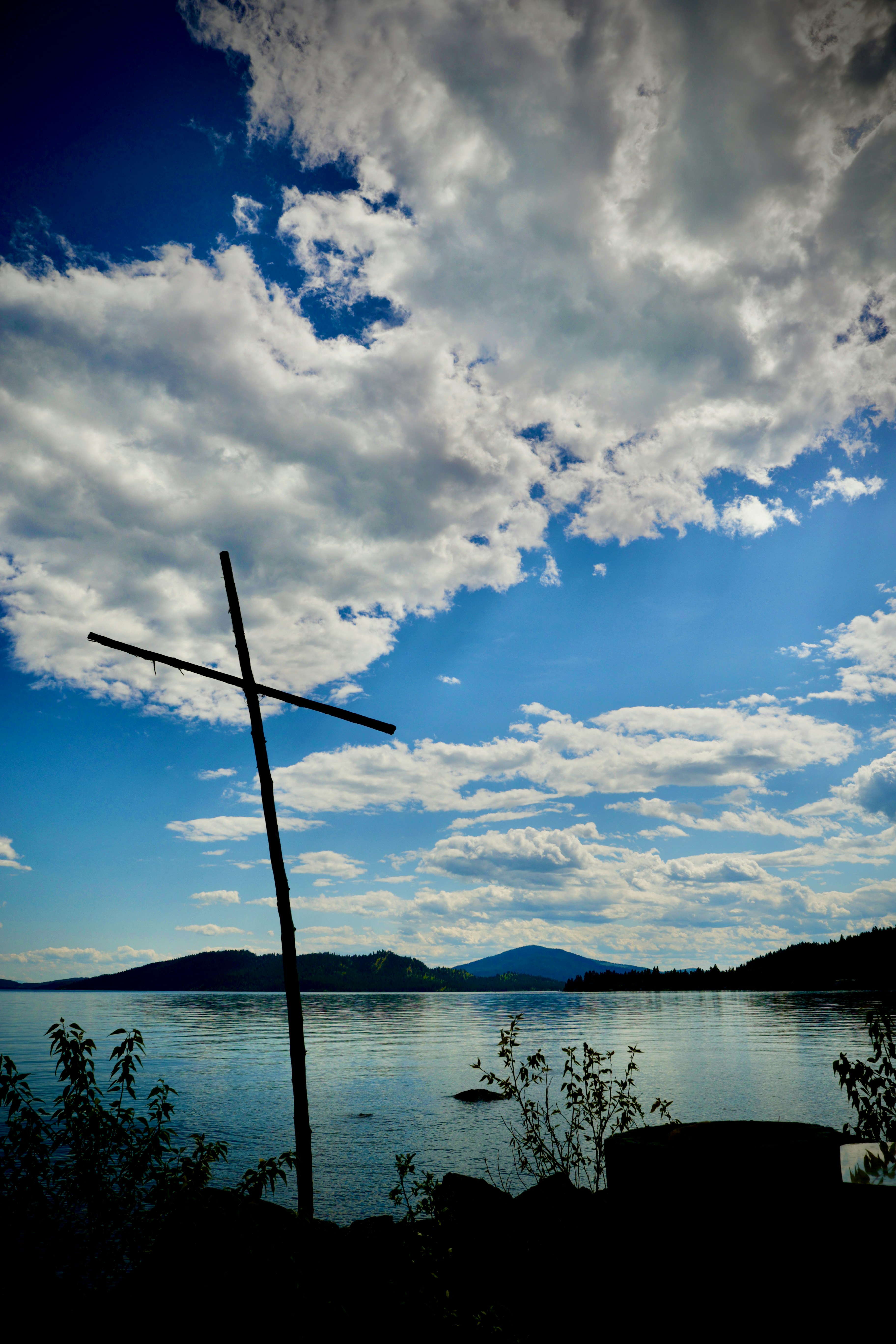 Lone Cross by the Serene Lake Under Expansive Sky