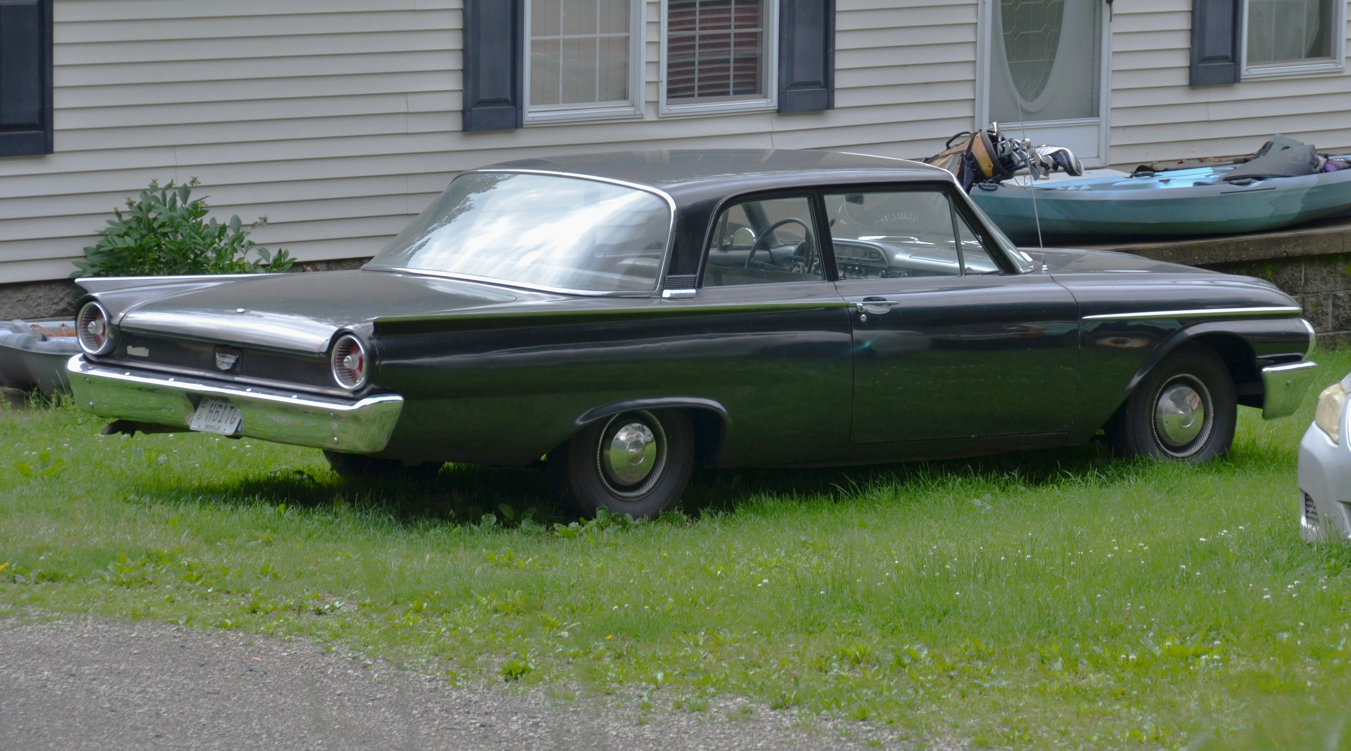 Mid-century Nostalgia: A Dark Green Classic Car Resting on a Grassy Lot