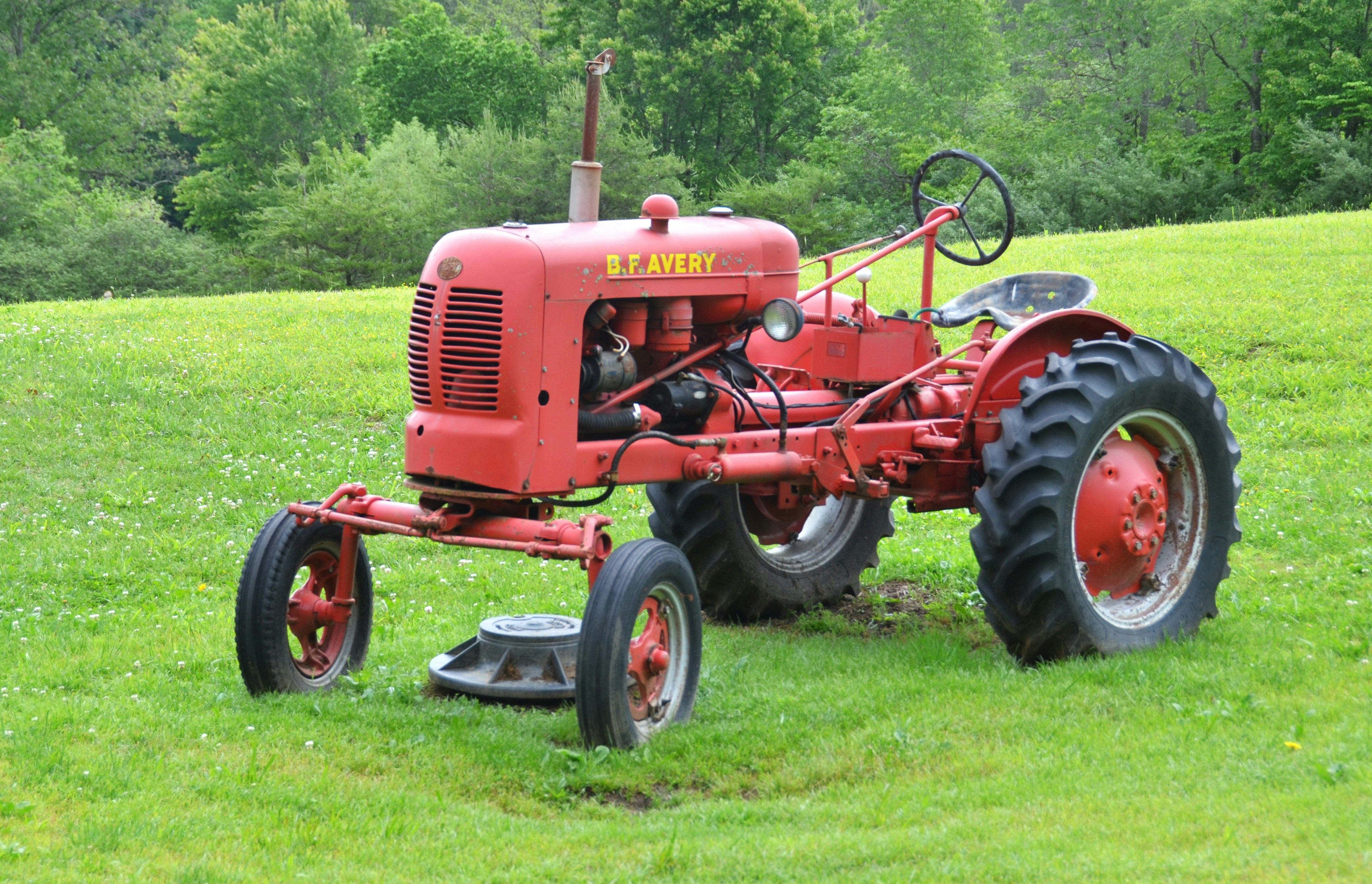 A vintage Avery tractor rests in a sunlit meadow