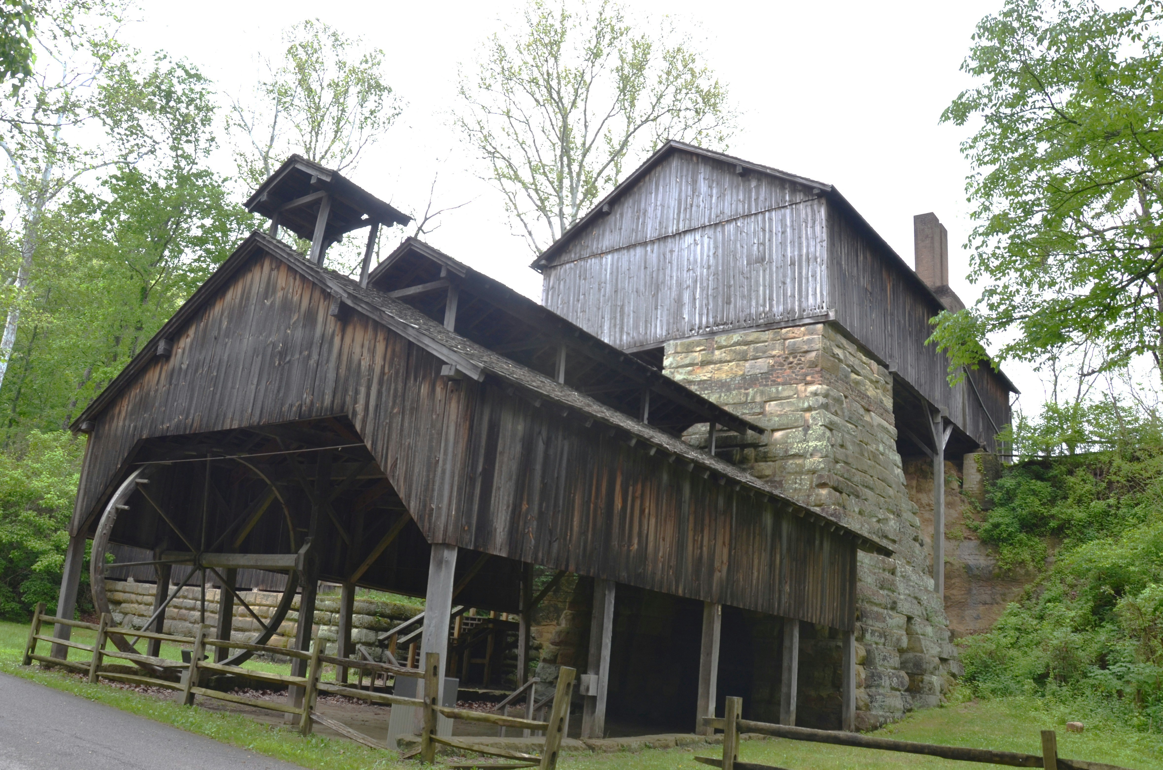 Wooden Watermill with Stone Chimney Rising from a Forested Embankment