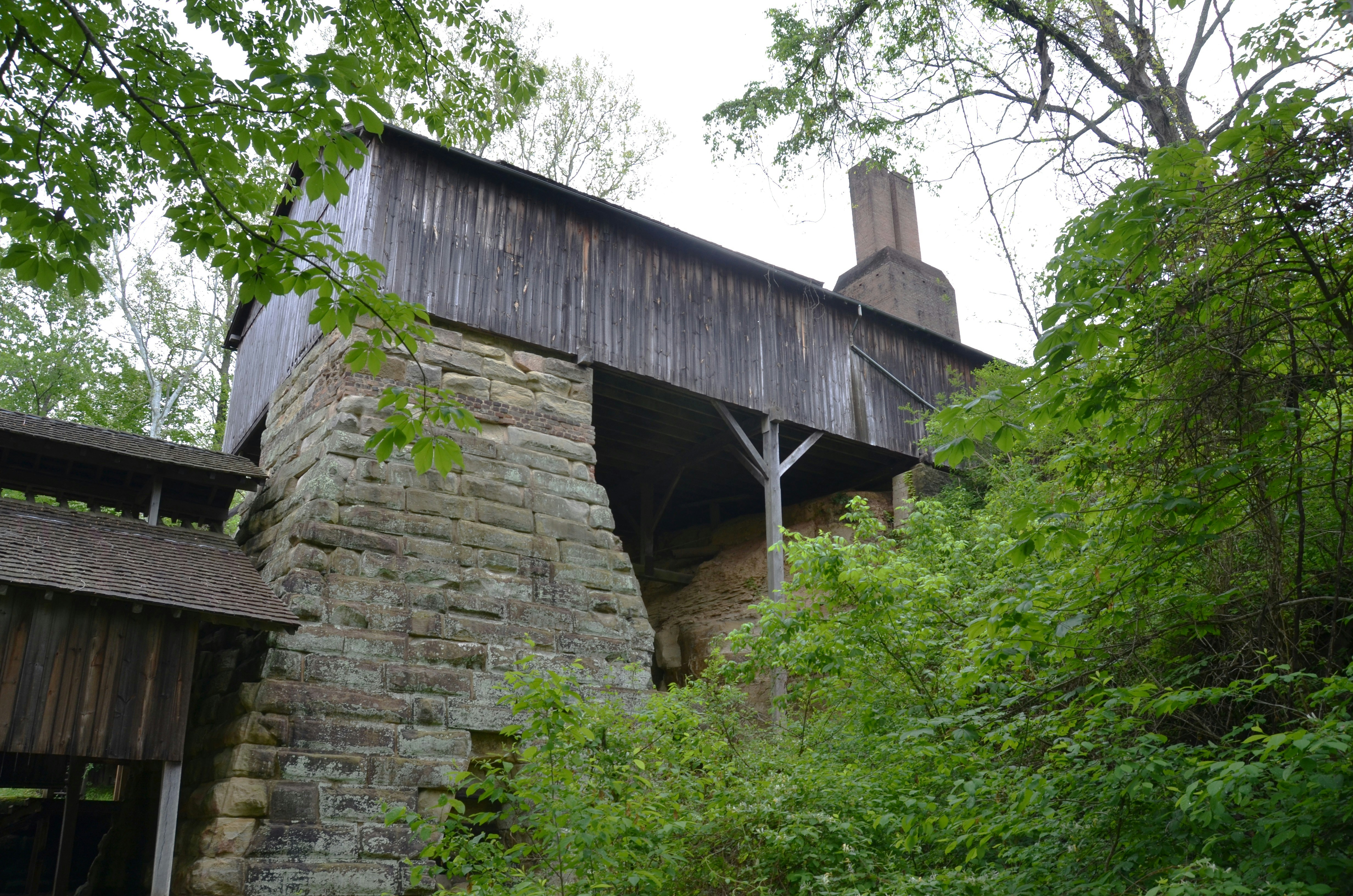 Ruined Mill Overgrown: Stone Walls and Wooden Hull Amid Greenery