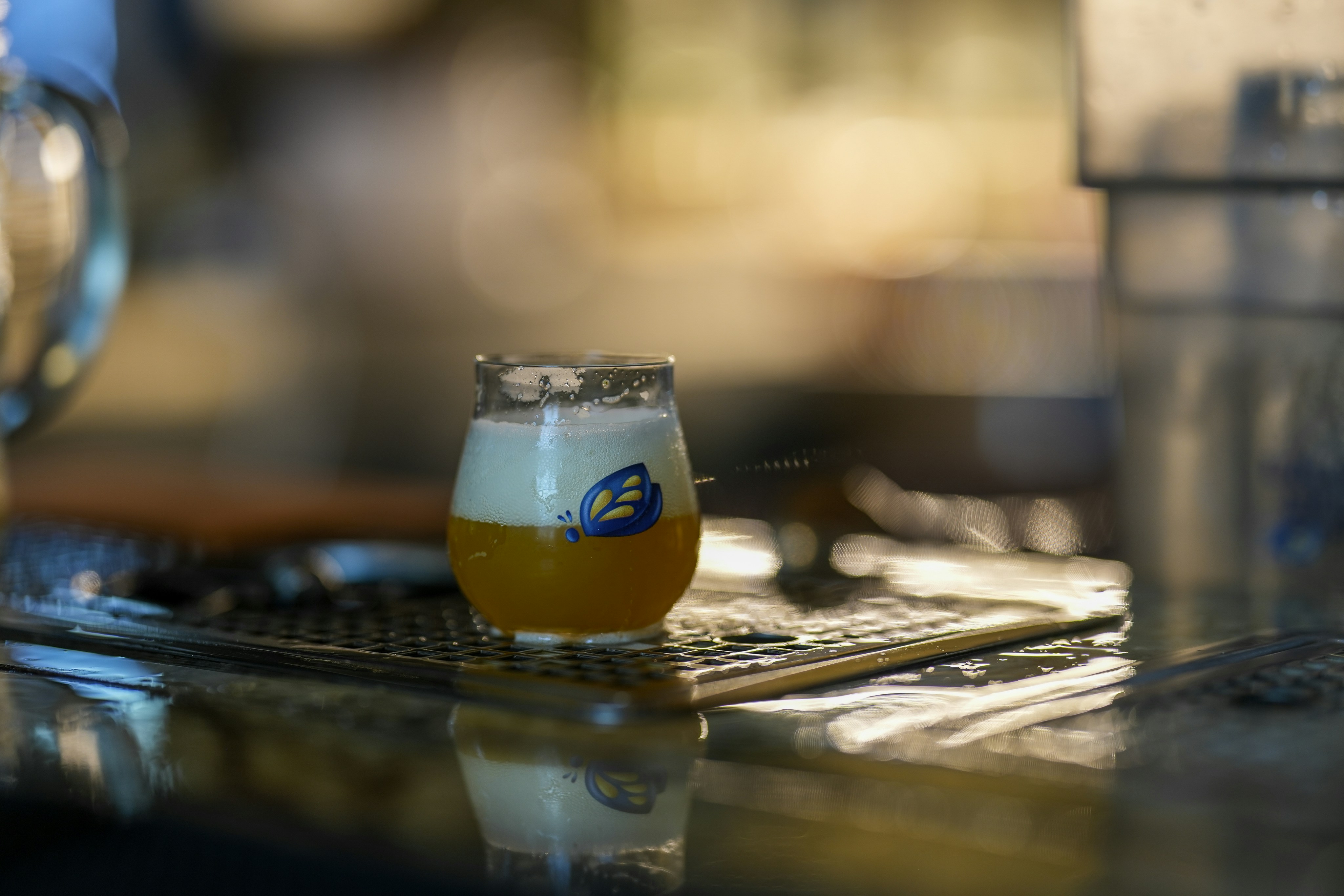Tiny Glass, Big Moment: A Craft Beer on a Reflective Bar Top