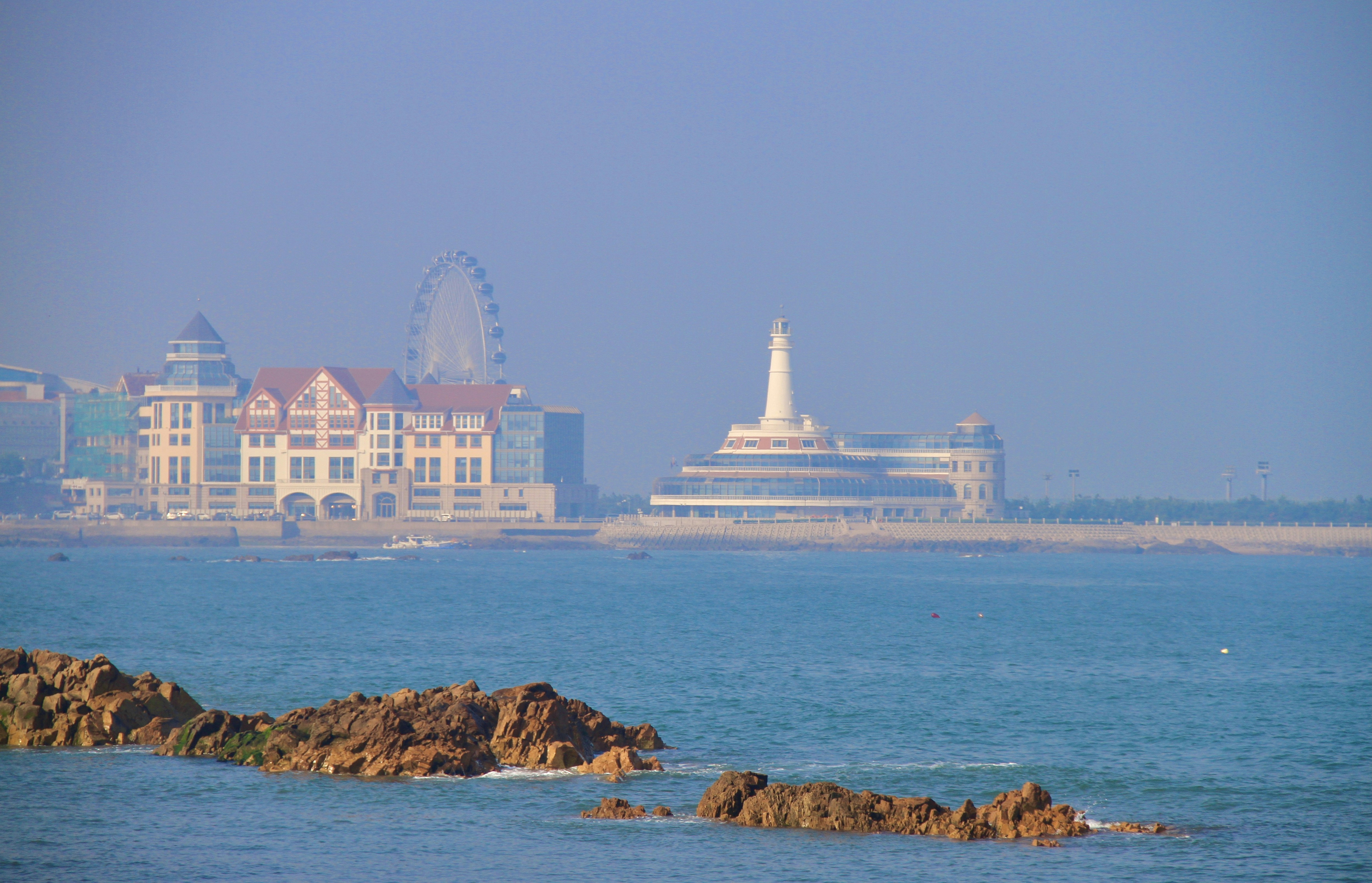 Harbor Promise: Ferris Wheel and Lighthouse Silhouettes Over Calm Sea