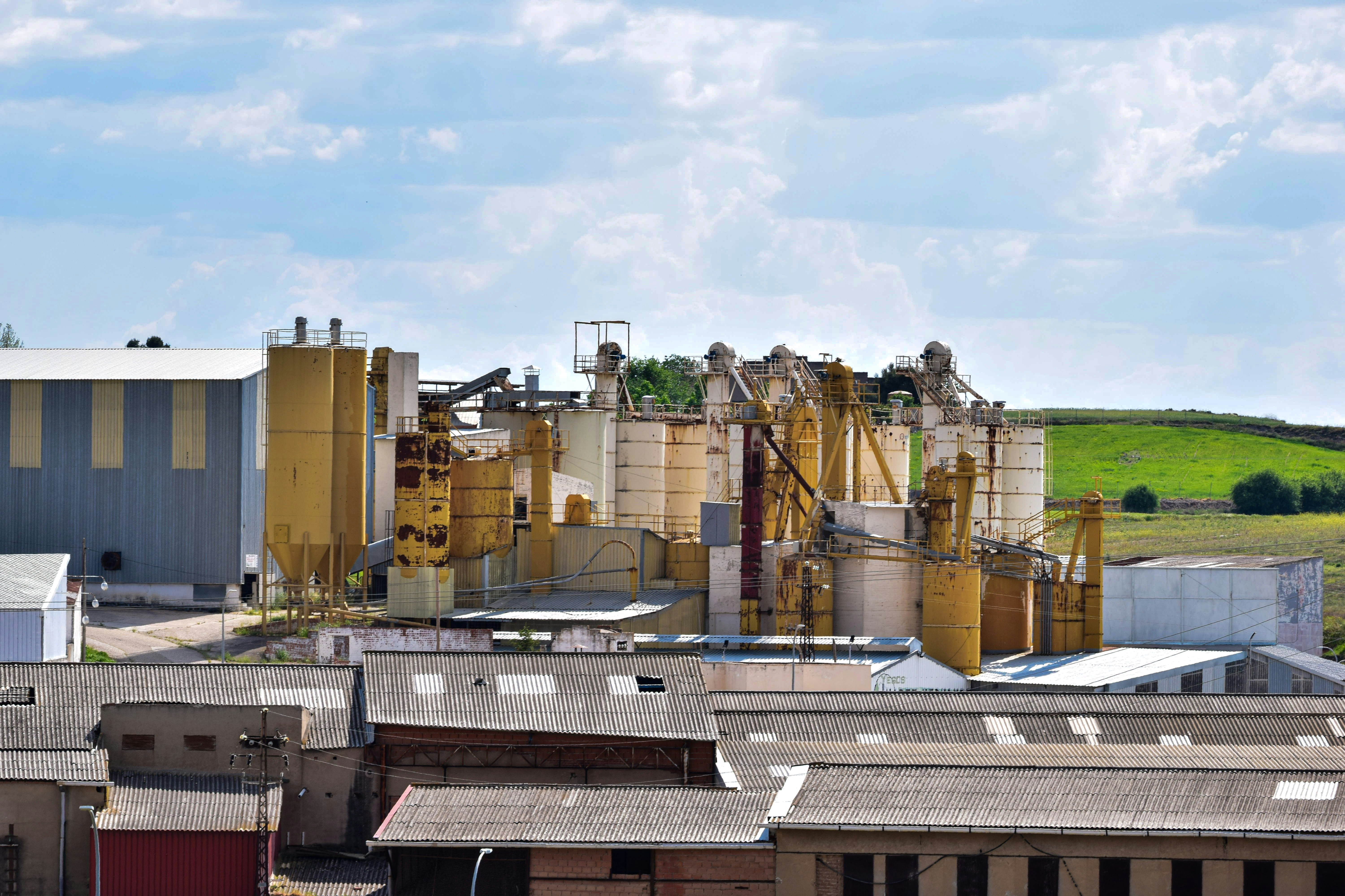 Industrial skyline: a row of weathered silos and rooftops under a bright sky