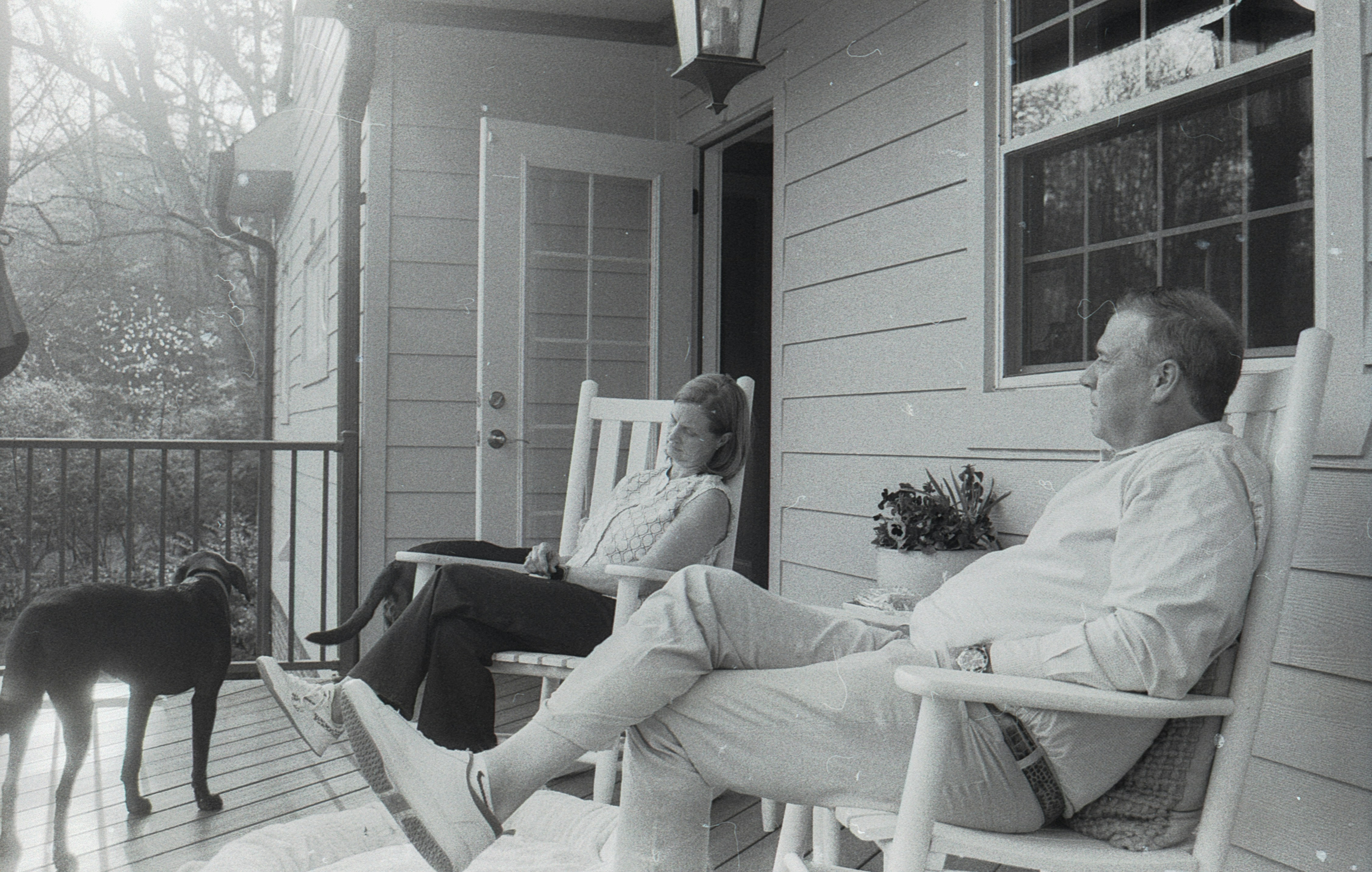 Quiet Porch Evening: Two Adults Relax with a Loyal Visitor