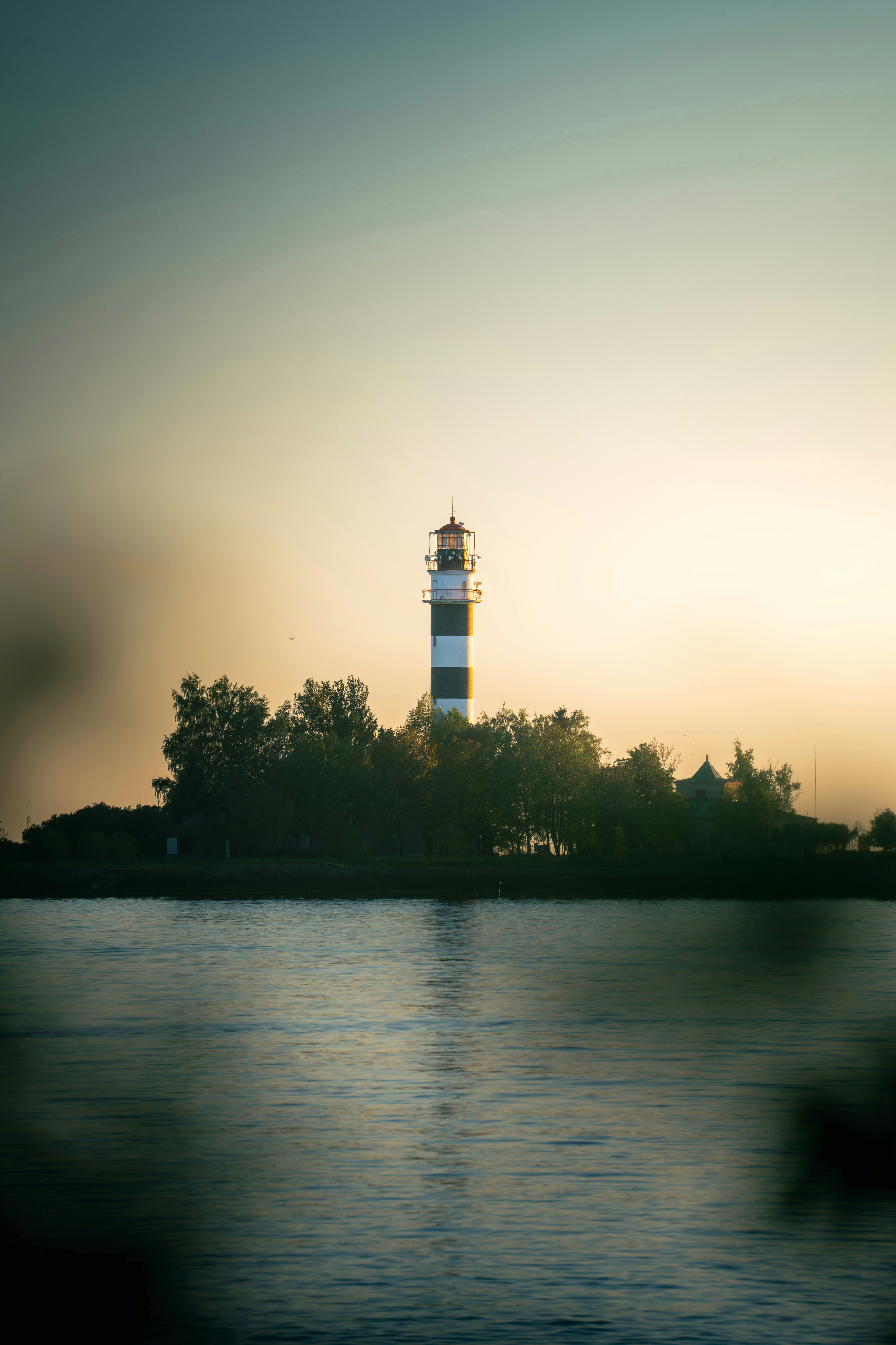 Beacon at Dusk: The Striped Sentinel Surrounded by Quiet Water
