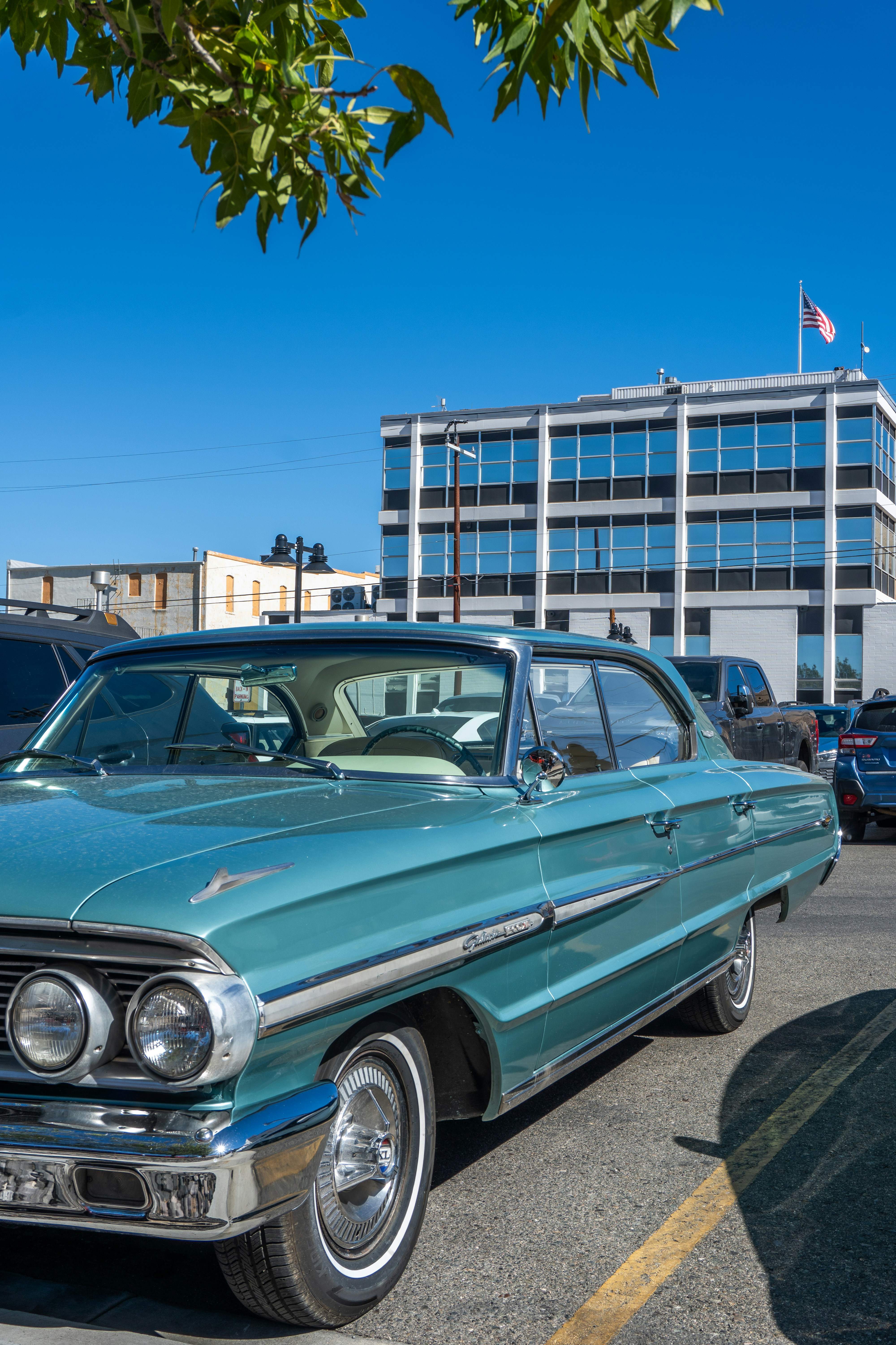 Classic teal car parked outdoors under a blue sky.