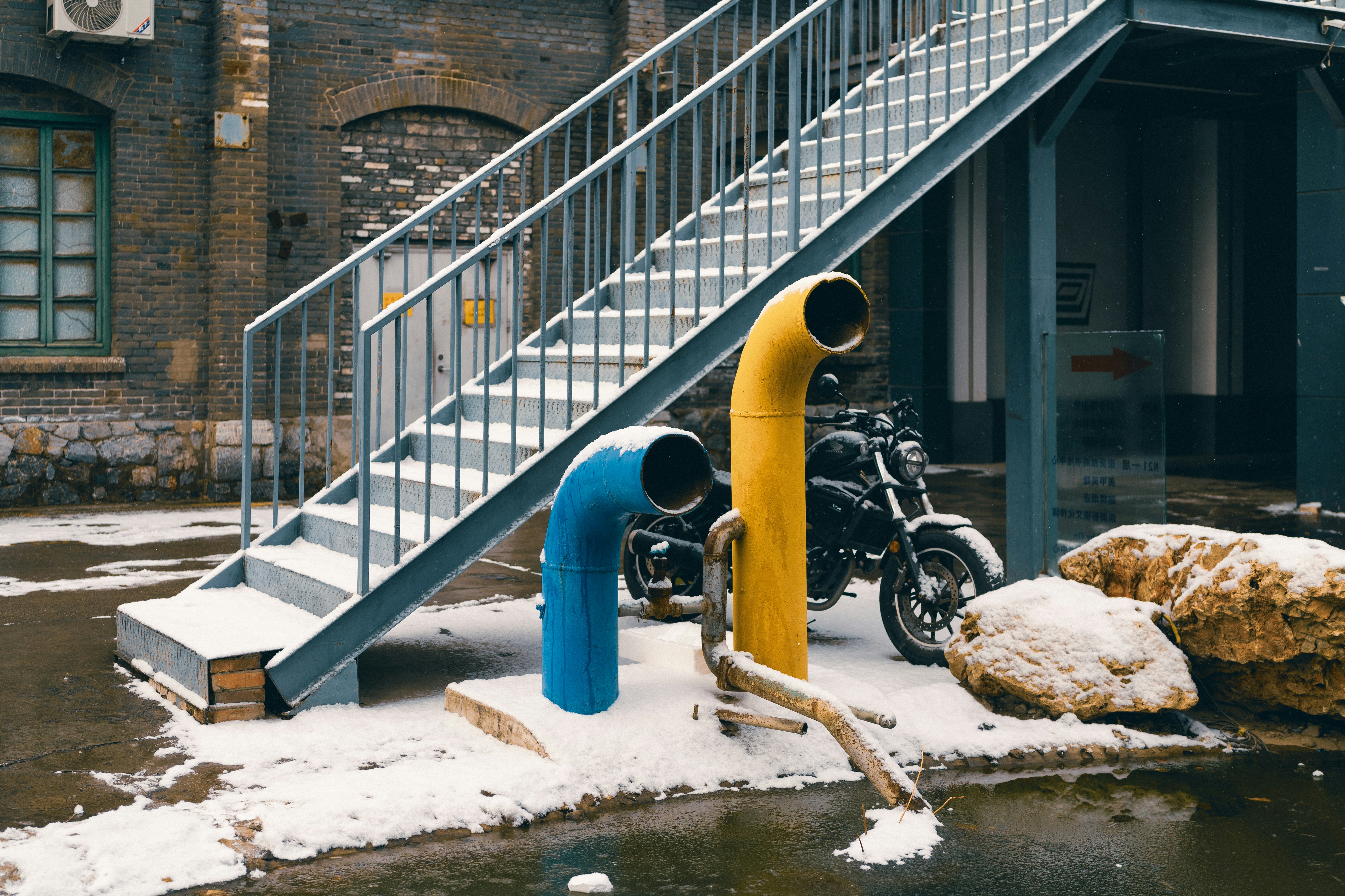 Industrial Courtyard Currents: Colorful Pipes Amid Snow and Steam
