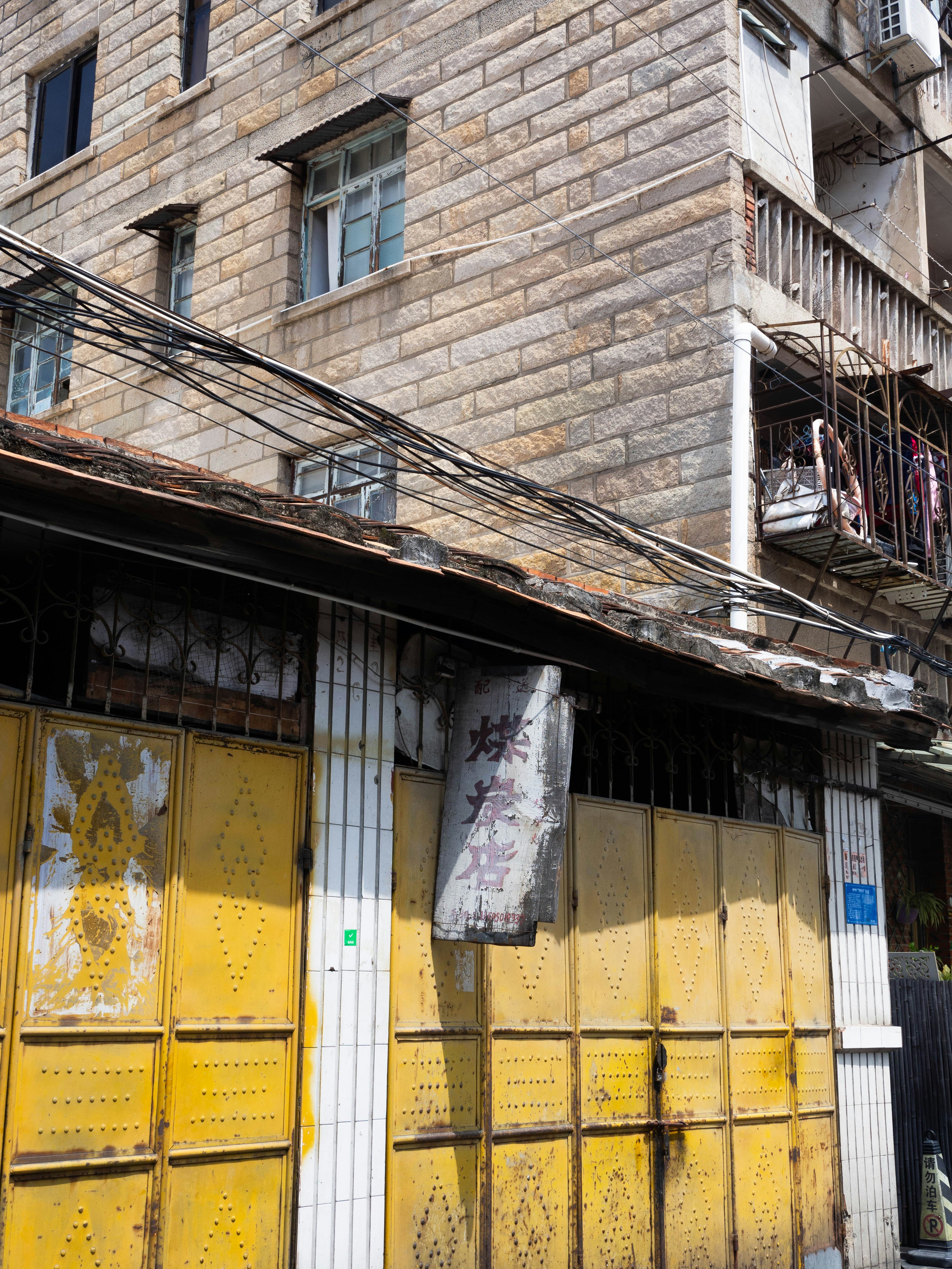 Yellow Gatekeeper: Cracked Facades and Laundry Above a Worn Balcony